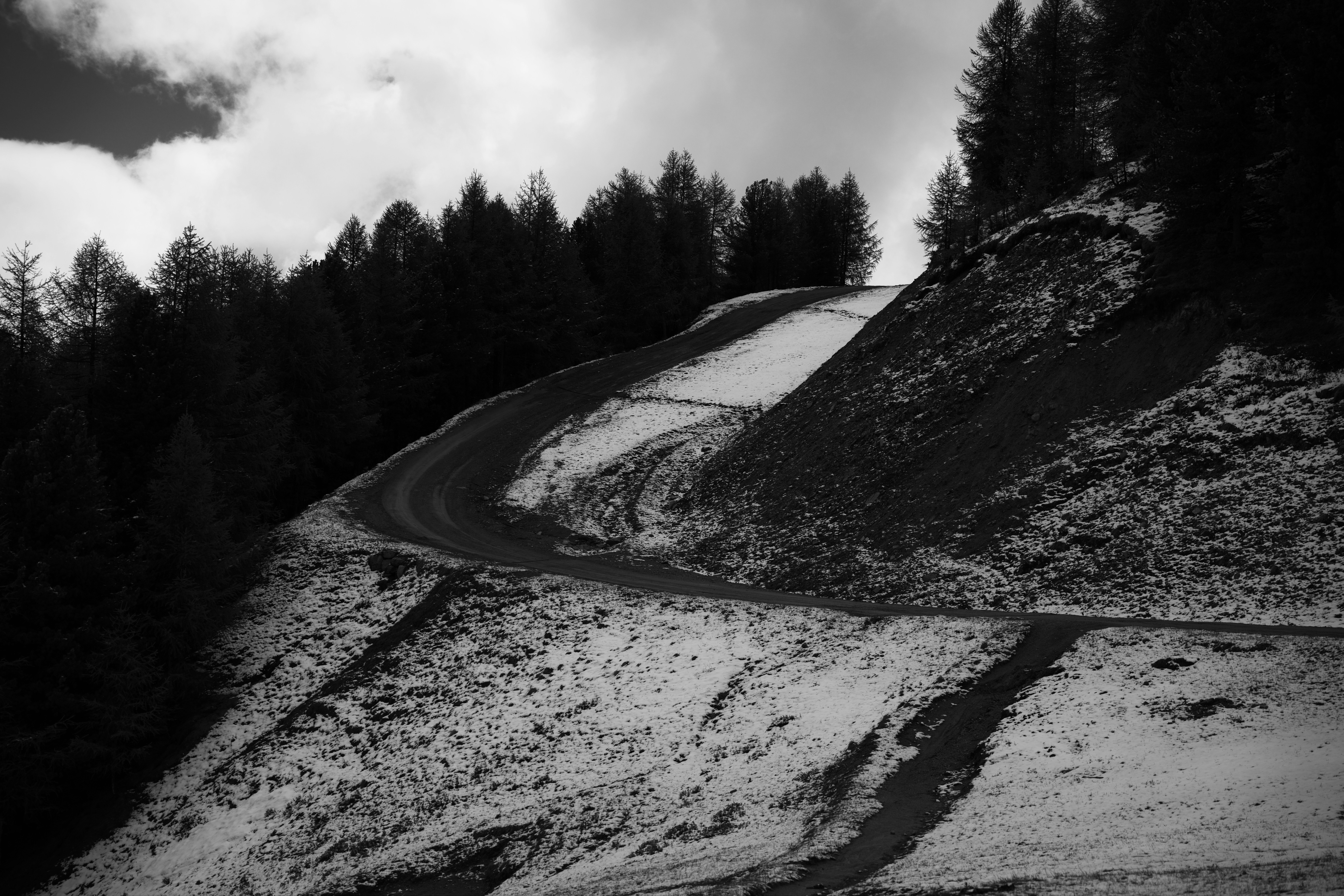Snow-veiled switchback: a lone road carving through a hillside