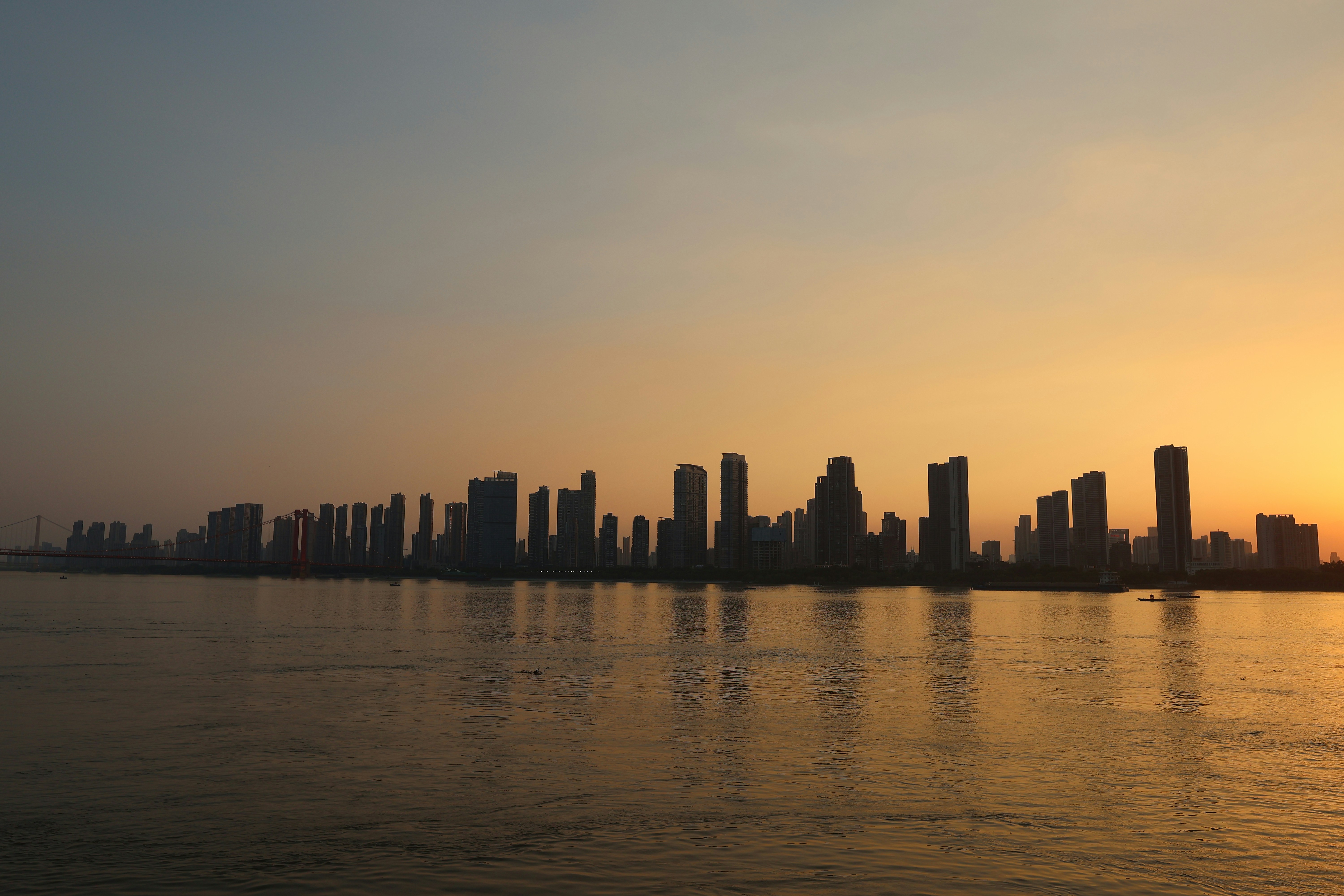 Sunset Silhouette: City Skyline Meeting the Calm Water