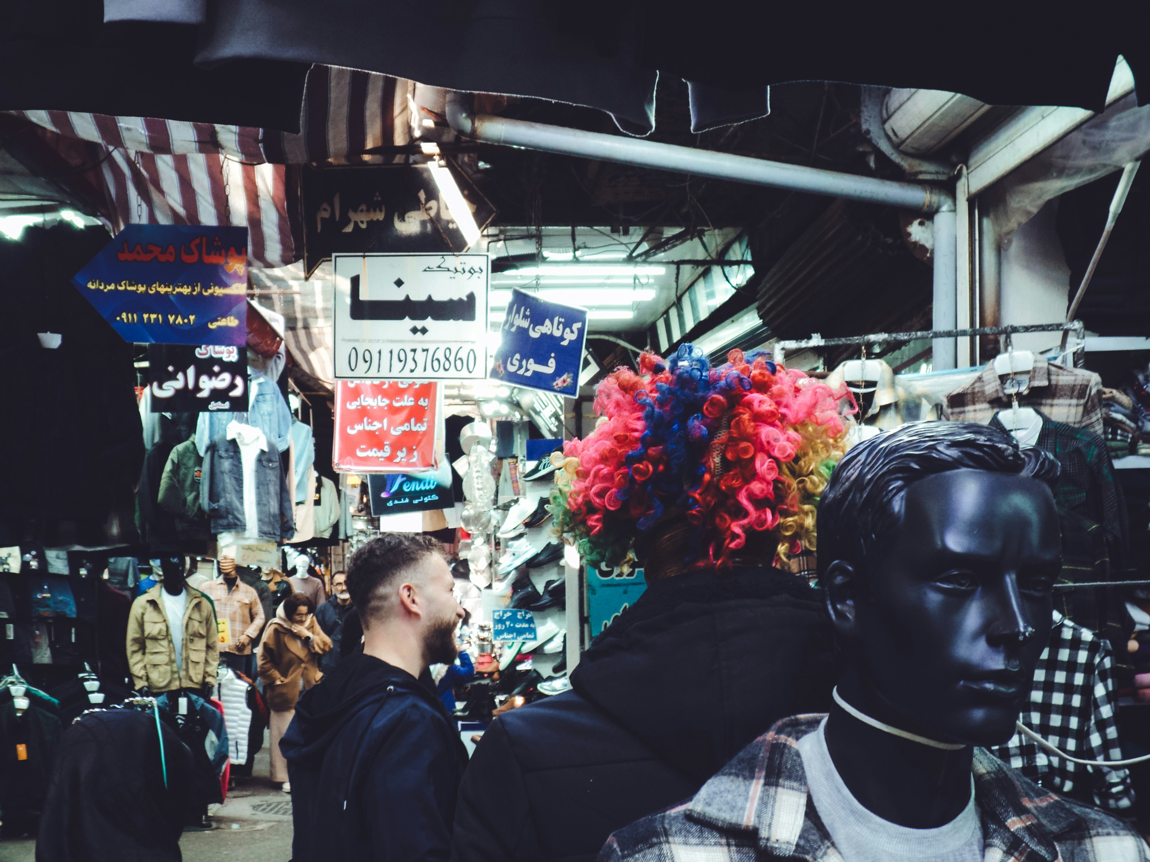 A stoic face of plastic watching the colorful chaos of the living.