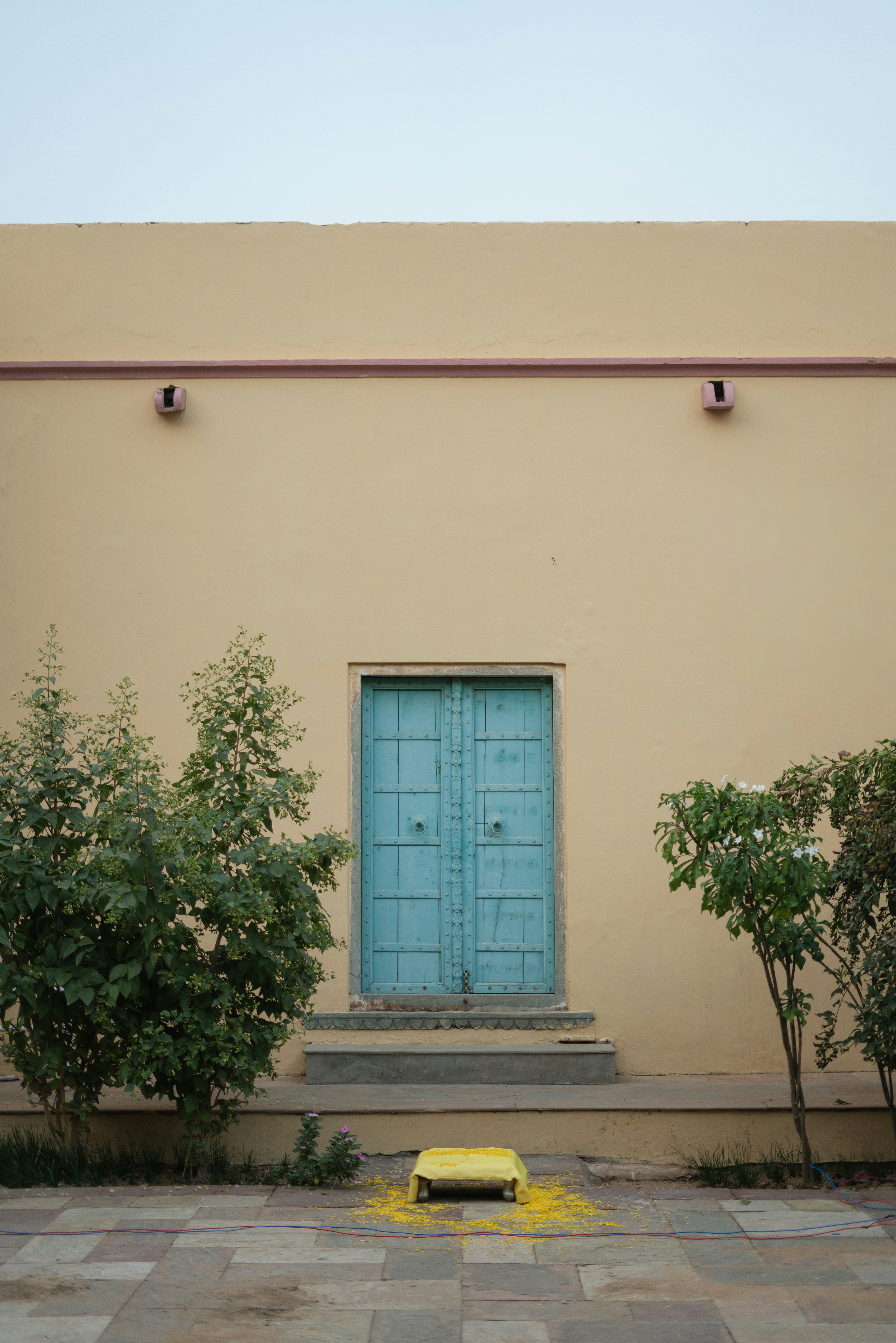 Pastel Facade with Sky-ward Gaze: A Quiet Doorway in Sunlit Urban Garden