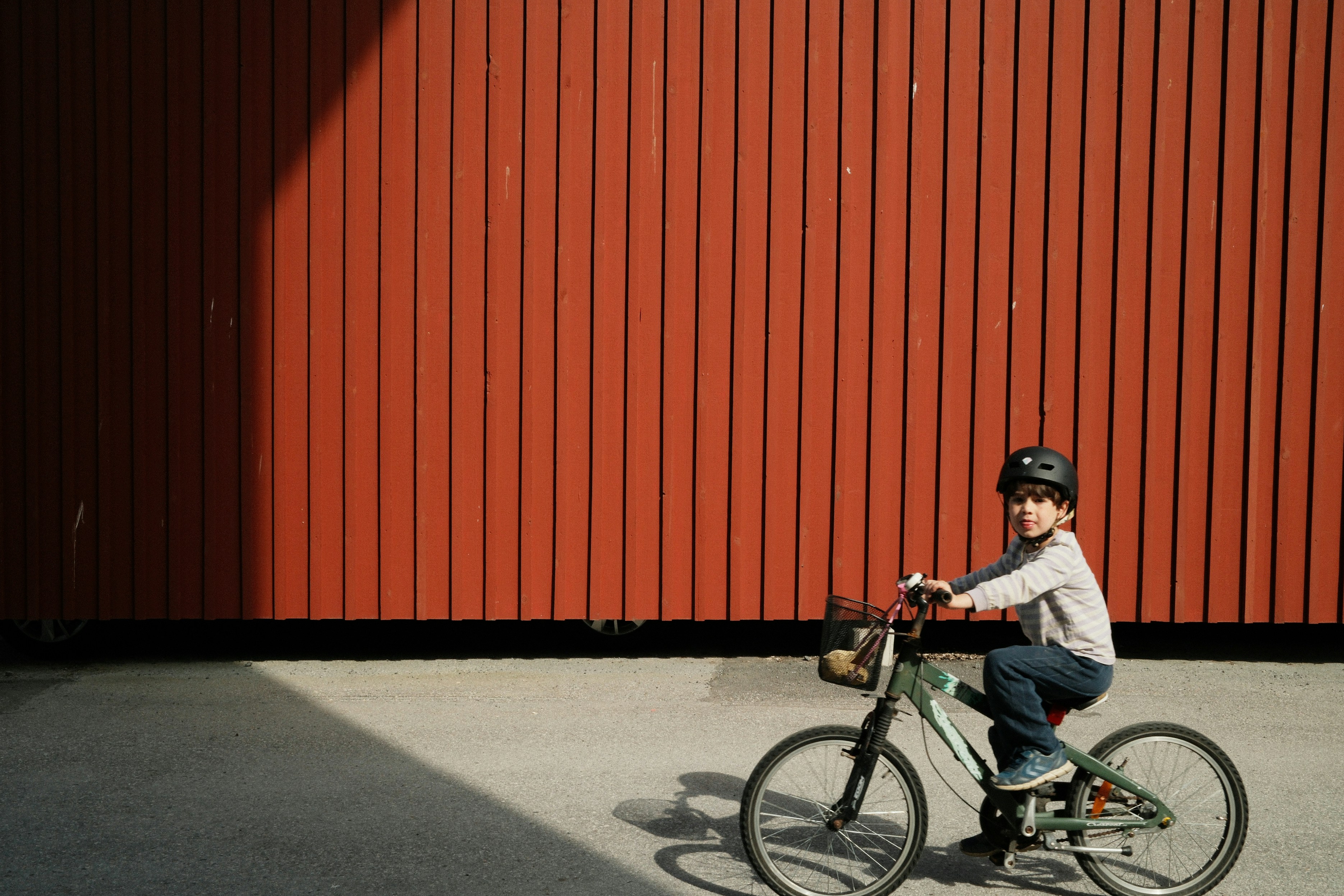 Child on a bicycle against a bold red wall