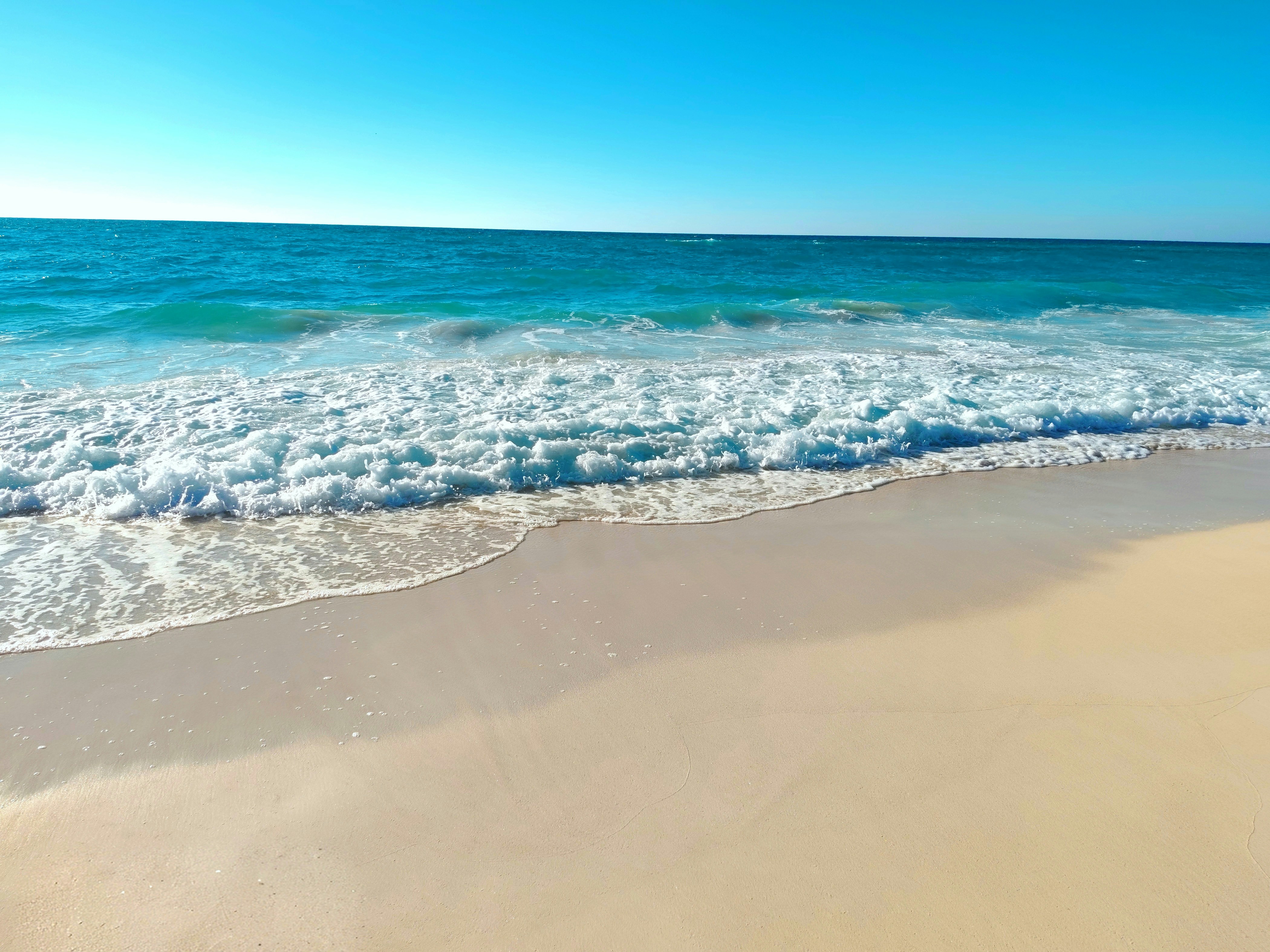 Sunlit Shoreline: A Quiet Moment Where Water meets Sand