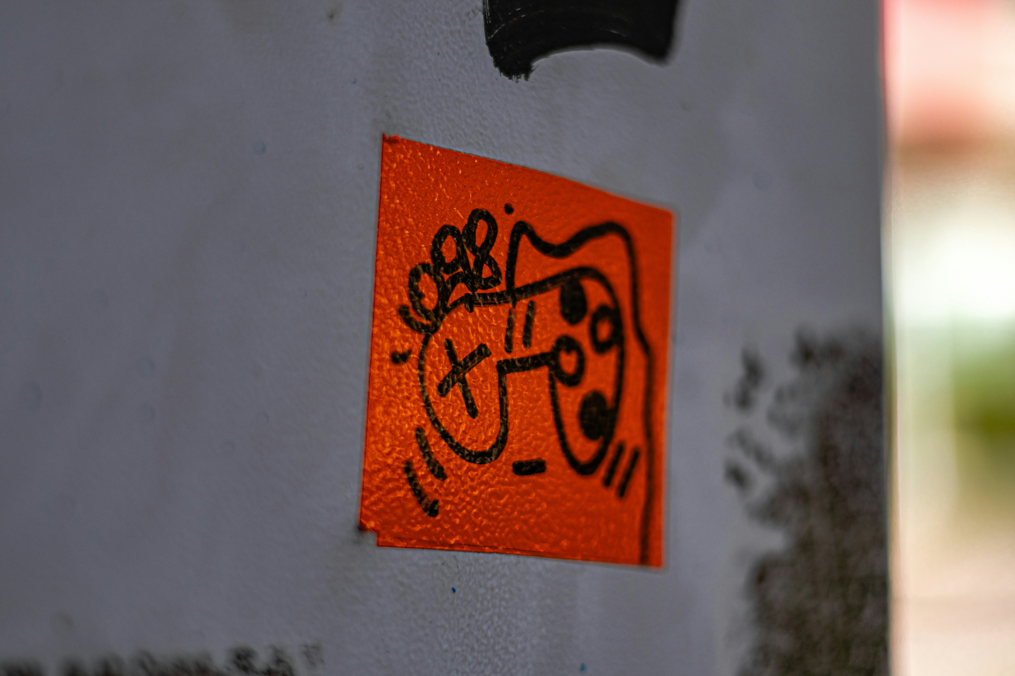 Orange sticker with doodle on a weathered surface