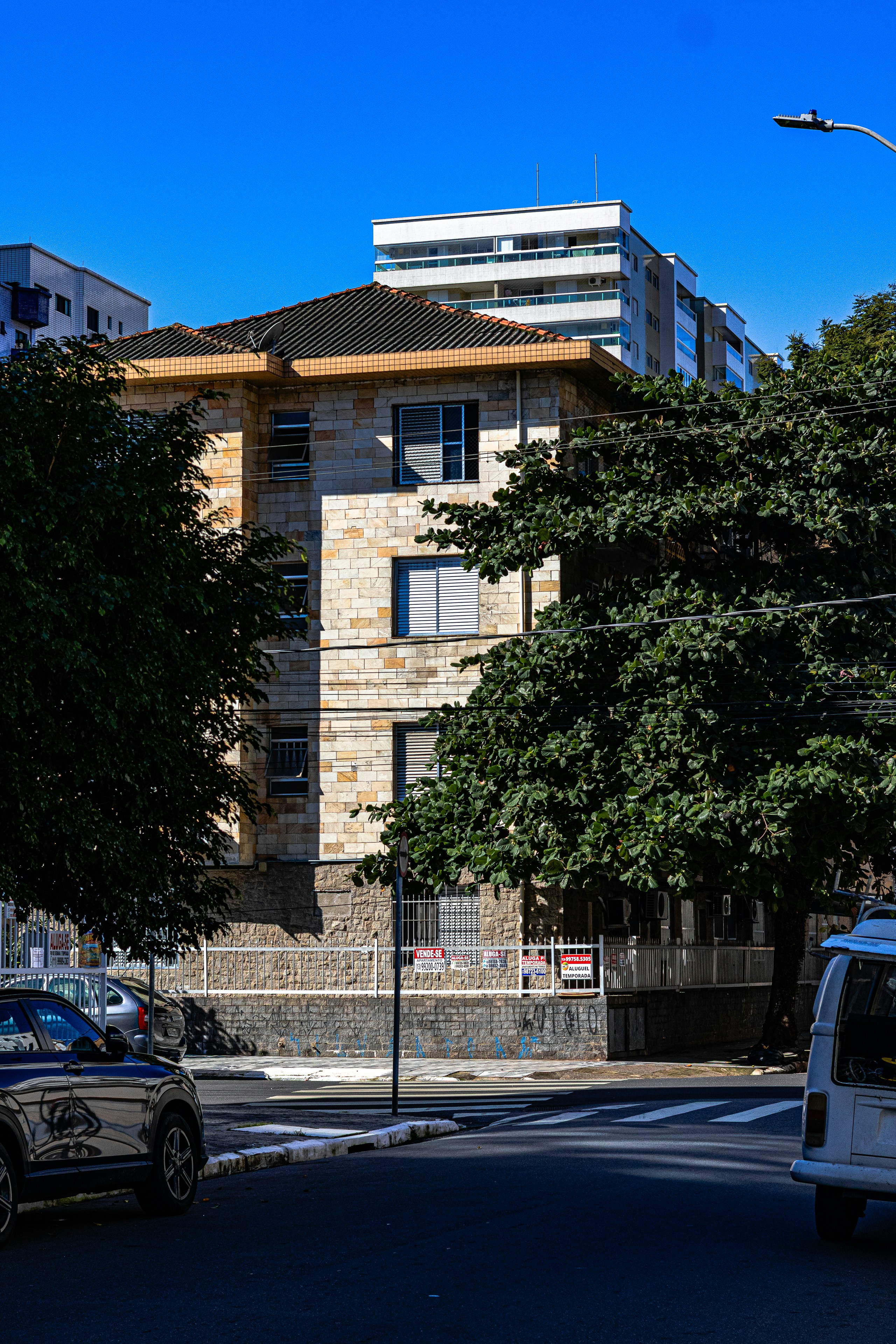 Sunlit Urban Facade: Stone Apartment Block Against a Clear Blue Sky