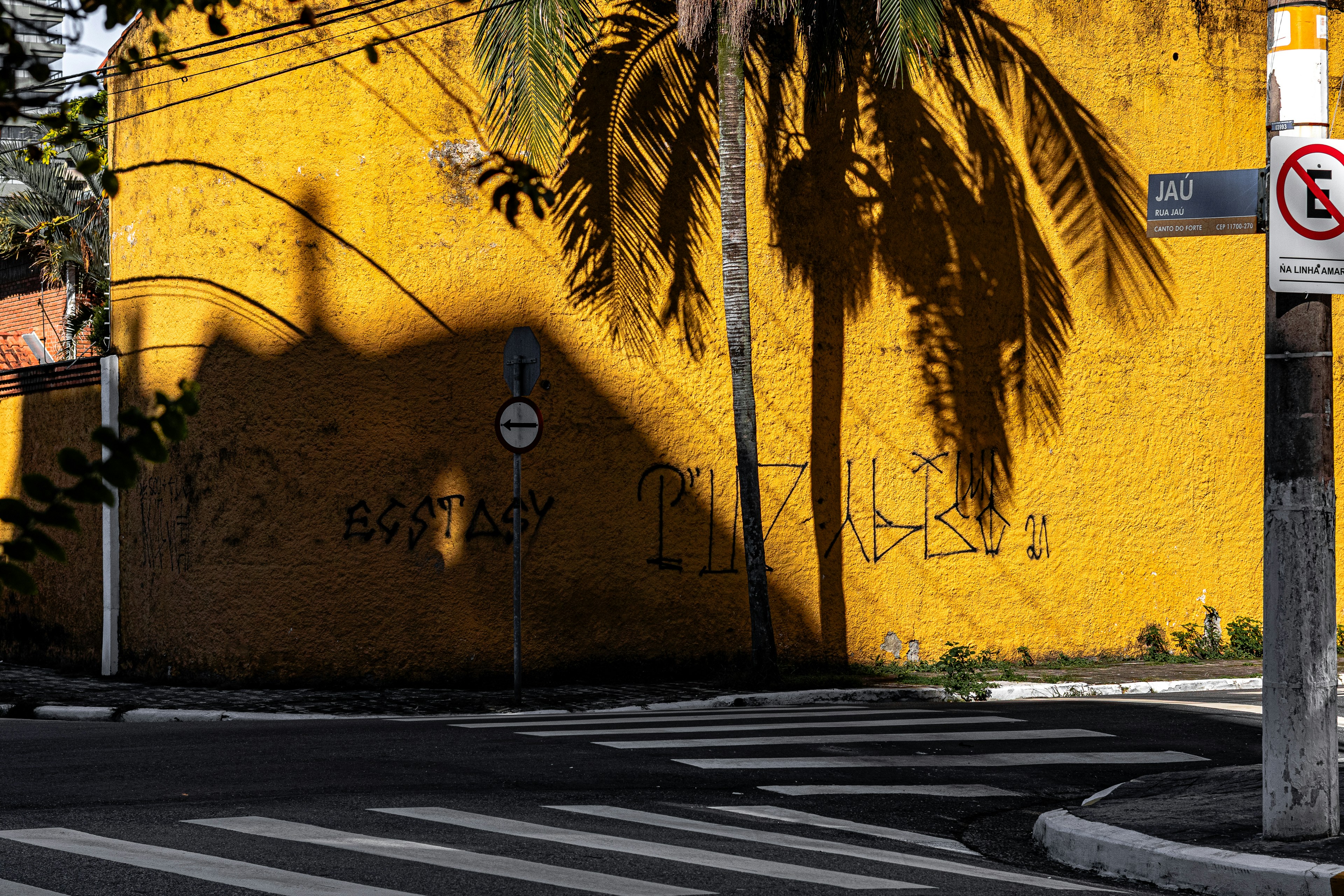 Golden Wall, Shadowed Crosswalk: Light and Graffiti at a Brazilian Street Corner