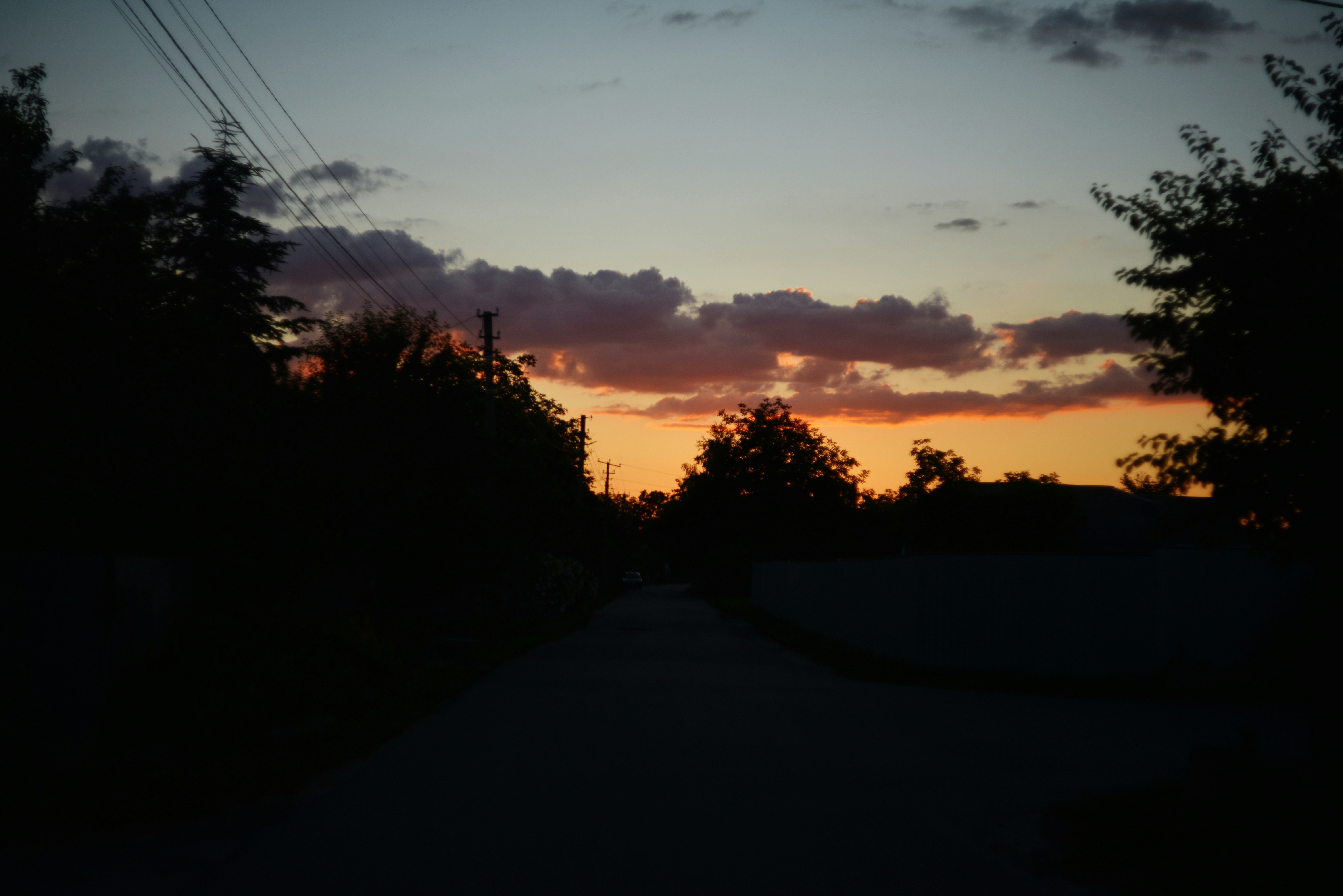 Dusk Roadscape: Silhouettes and Sunlit Clouds