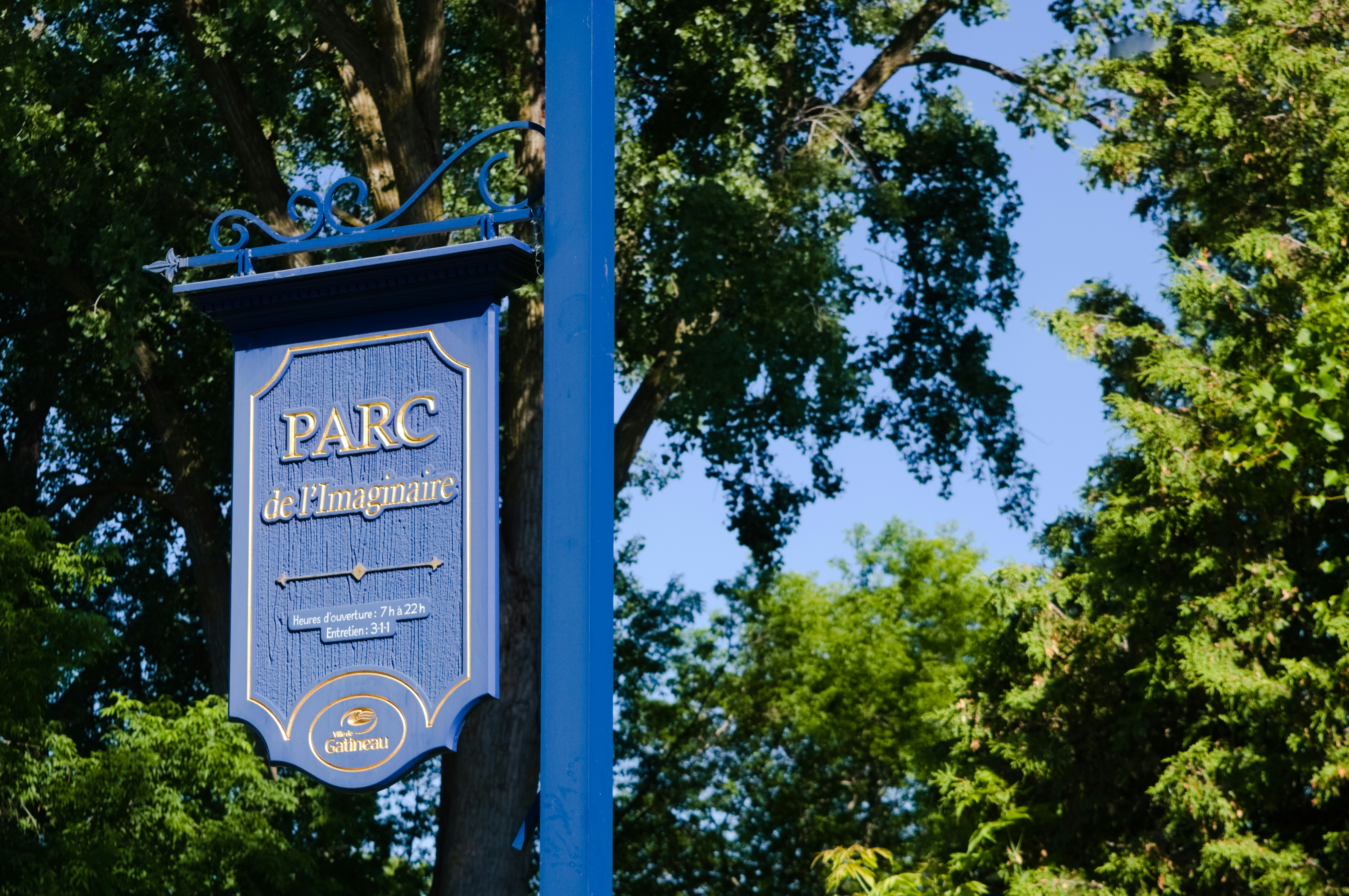 Parc de l'Imagination: A Blue Sign Amid Sunlit Foliage