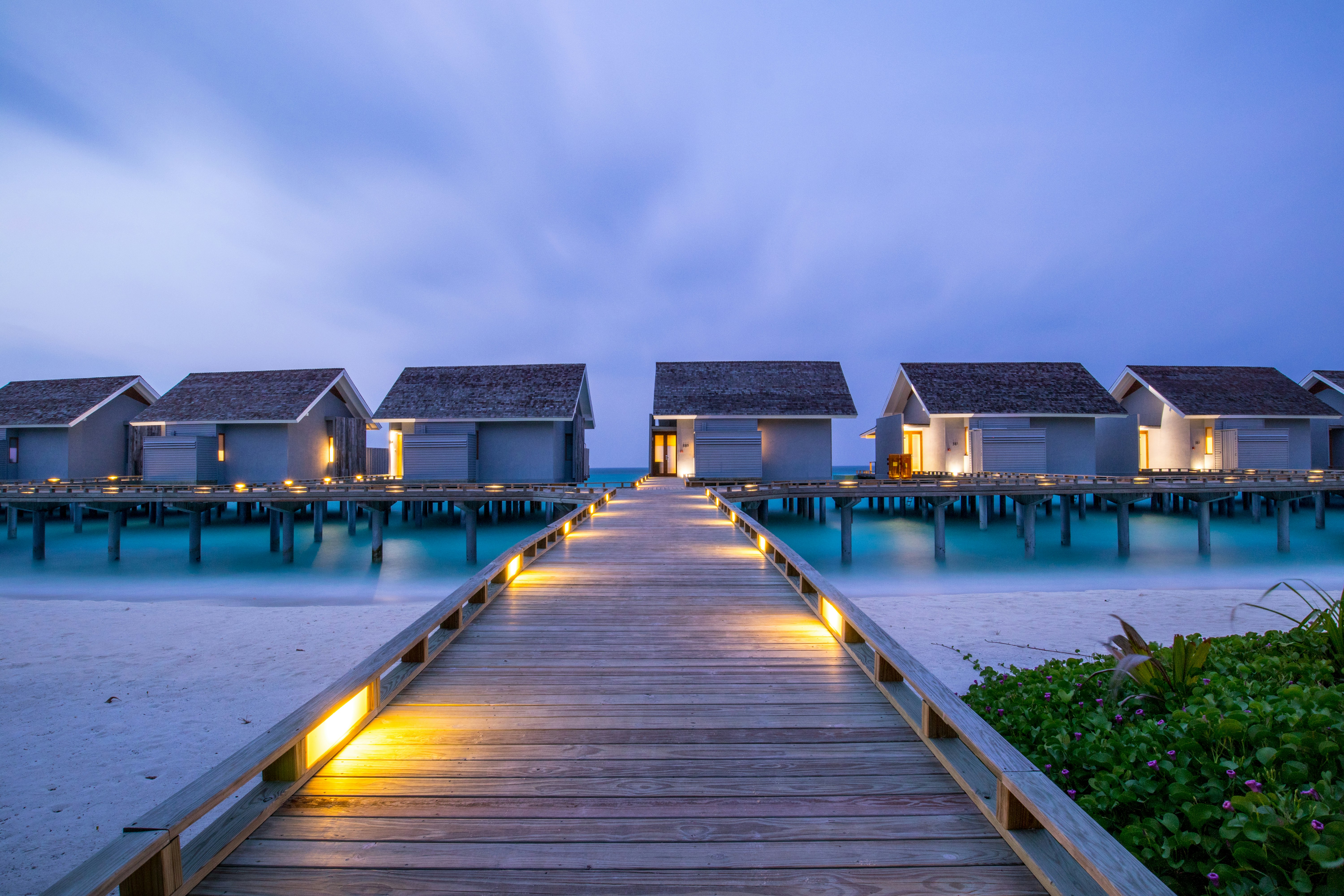 Symmetrical Overwater Pier: A Row of Oceanic Bungalows Illuminated at Dusk