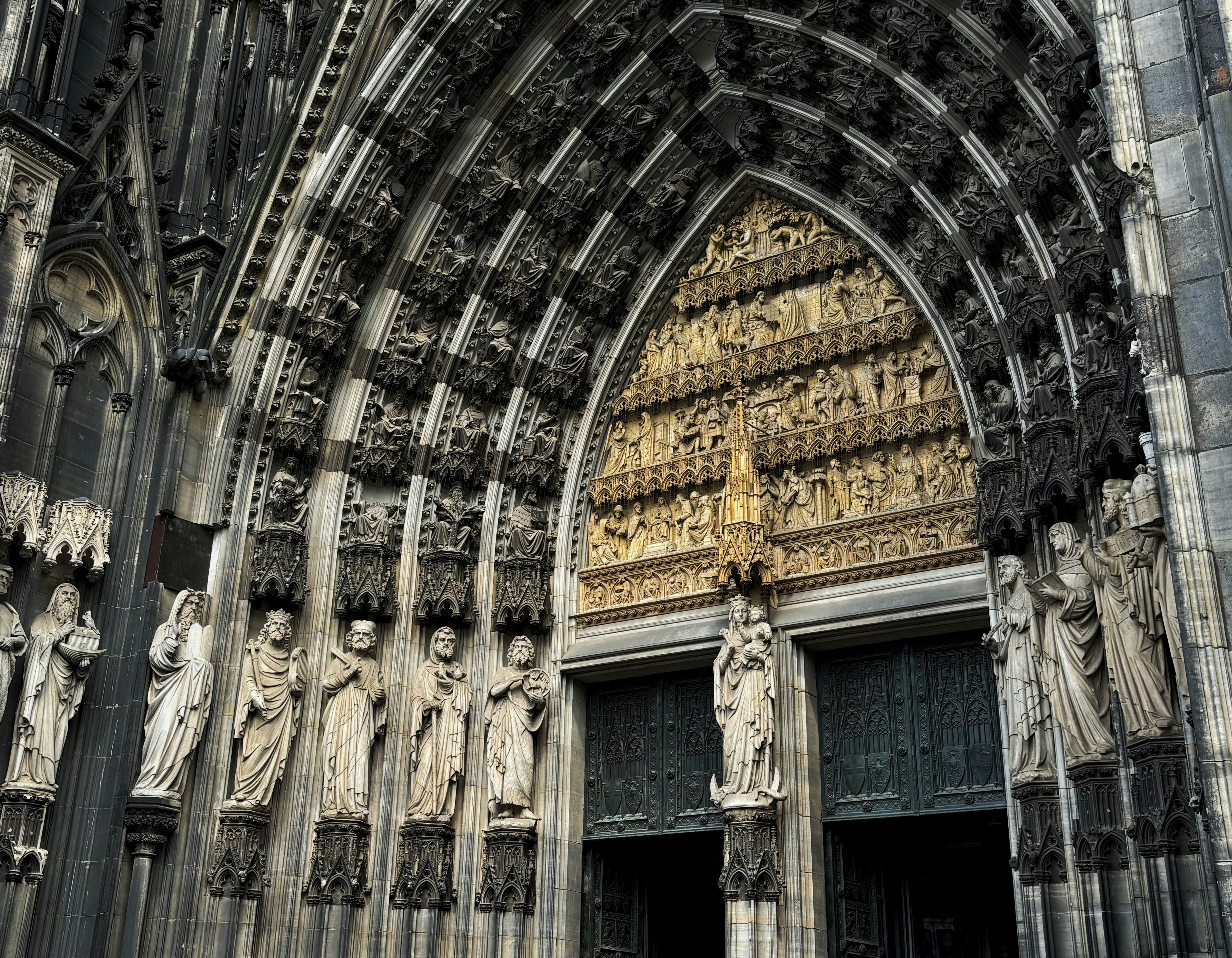 Intricately carved gothic portal with statues and detailed stonework dominates a grand doorway.