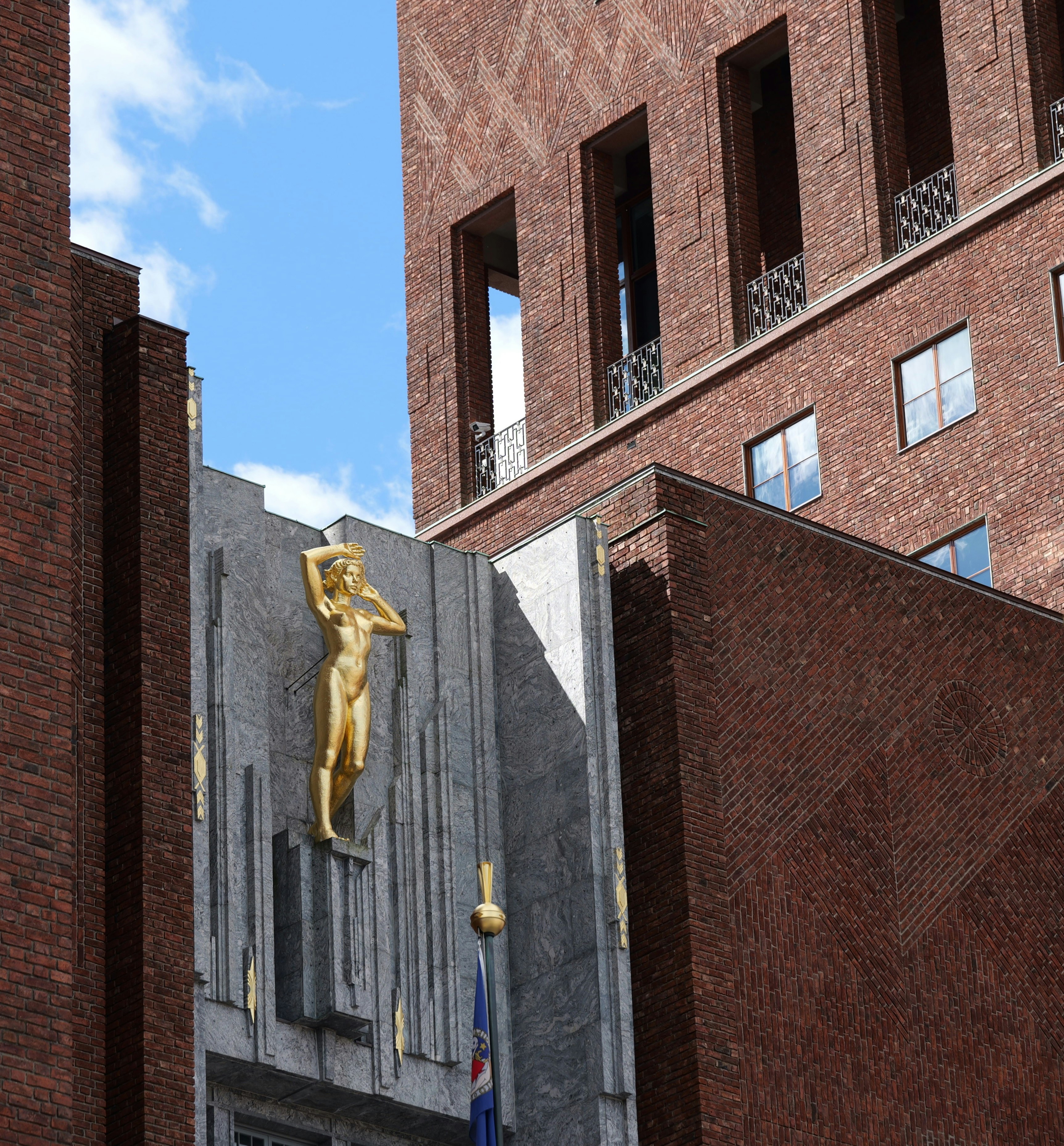 Golden Figure Guarding the City: A Statue Amid Brick Facades