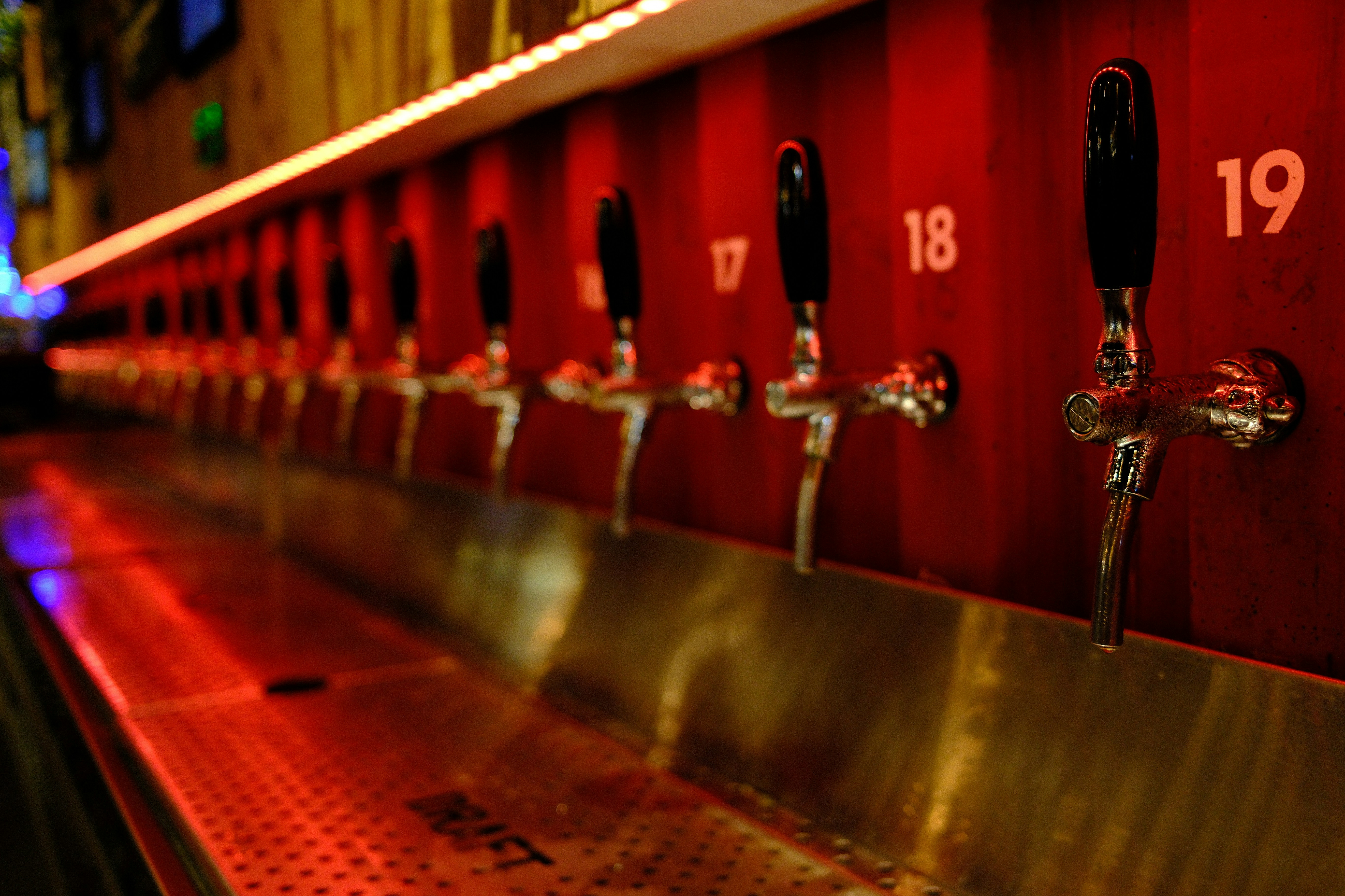 Red Tap Cascade: Row of Beer Taps in a Neon-Soaked Bar