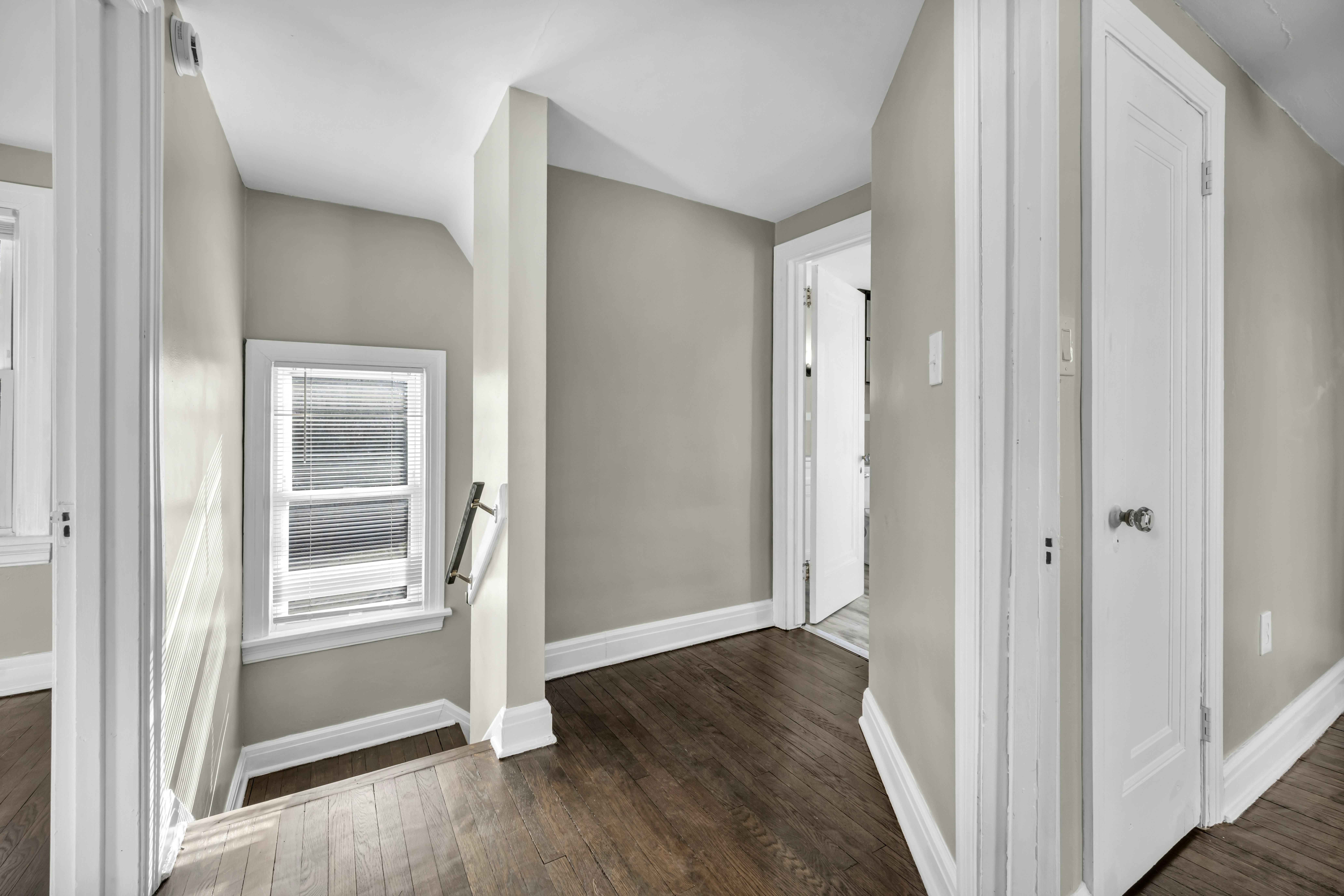 Softly Lit Hallway with Stairwell and Open Doorways