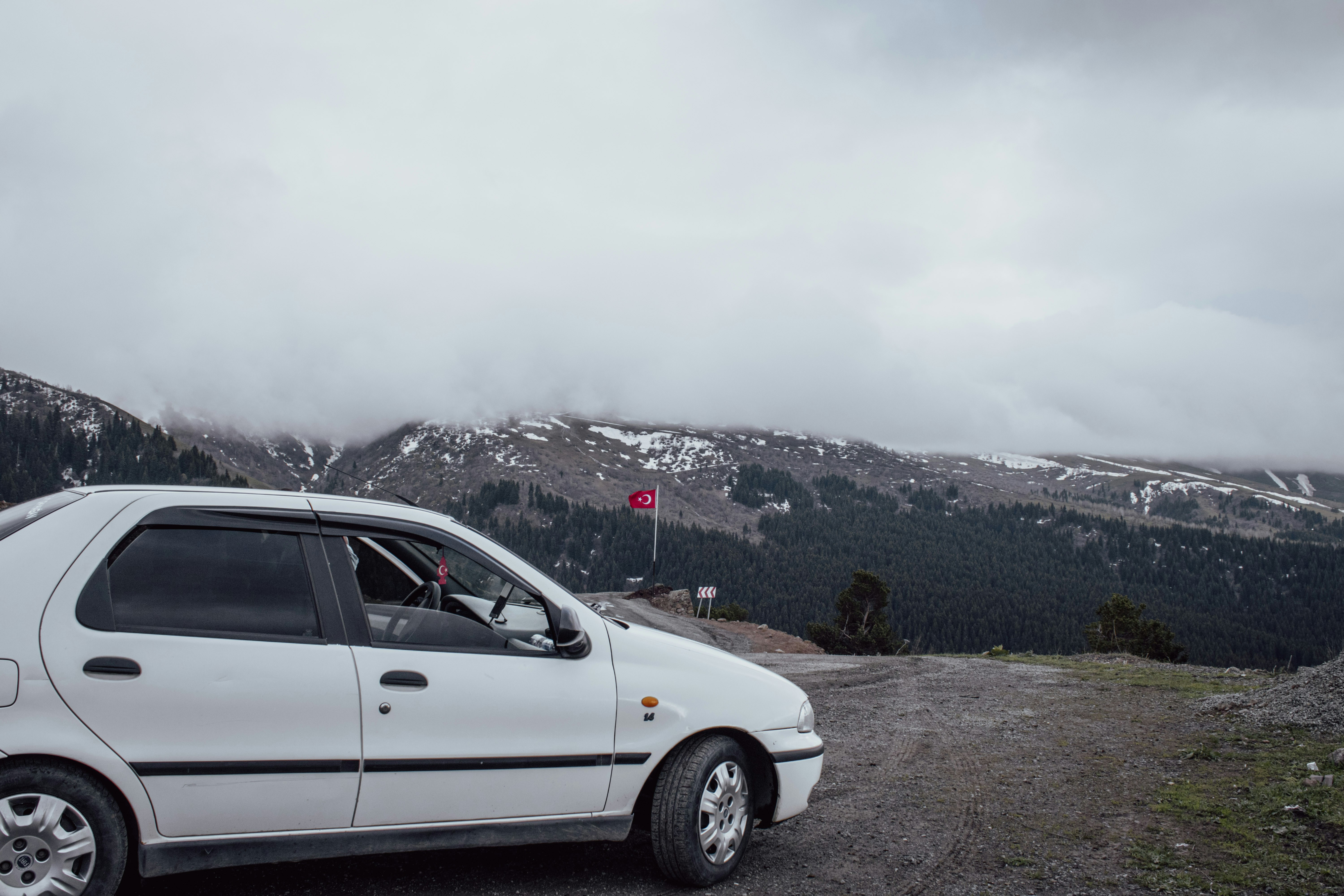 White hatchback at a mountain overlook under cloudy skies