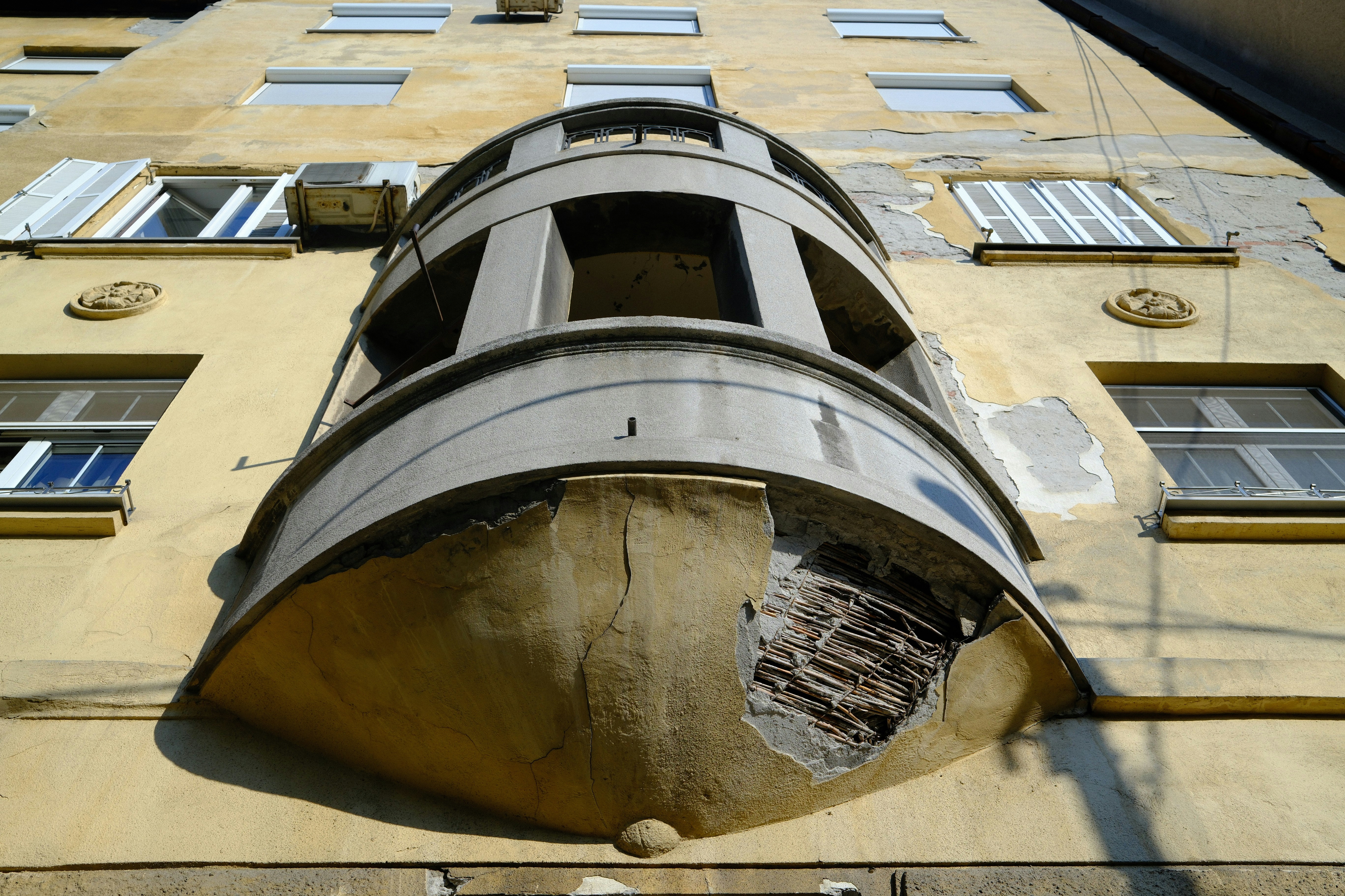 Weathered Balcony Torch: A Curved Facade of Decay