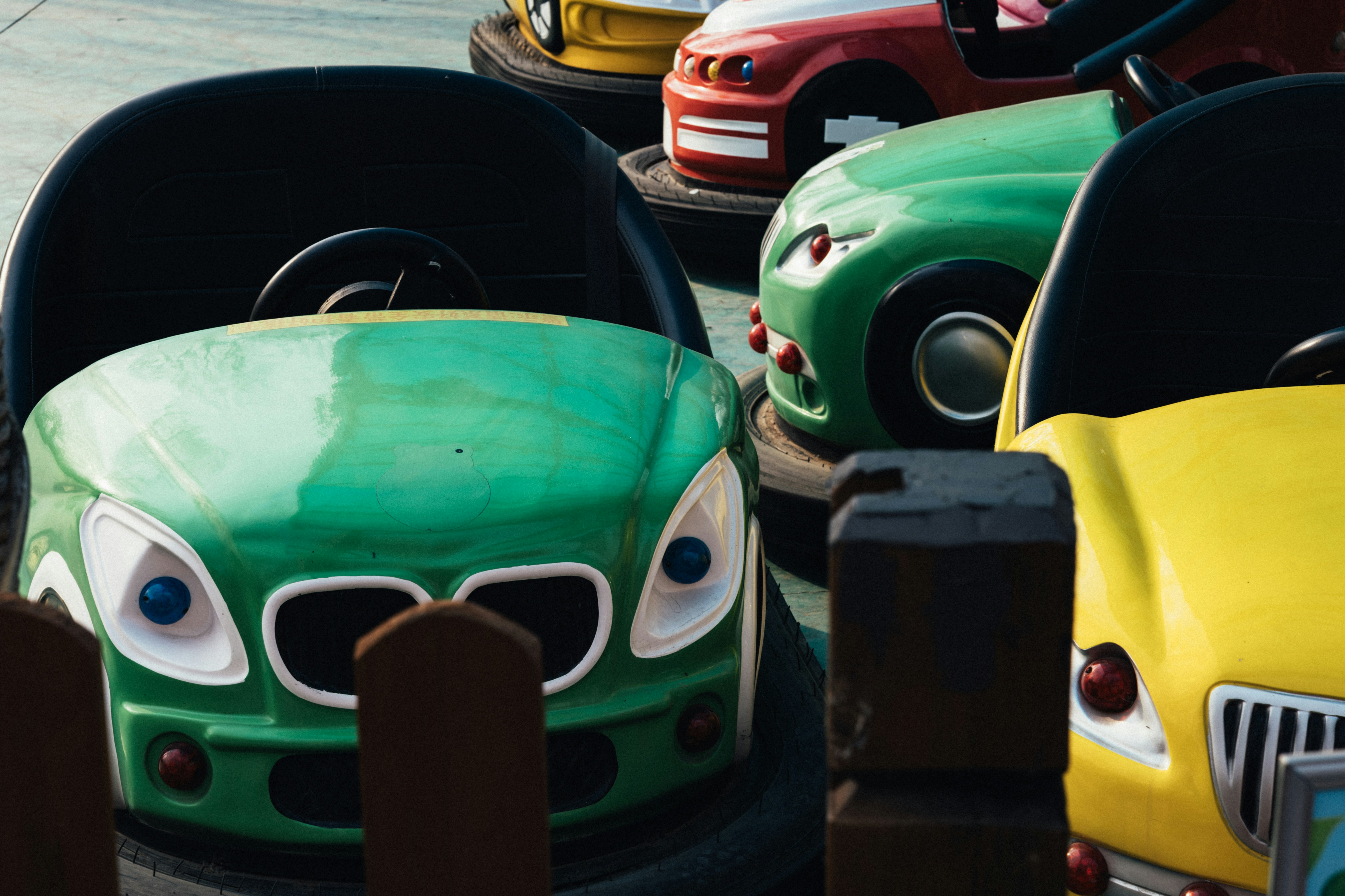 Colorful Tilt-A-Whirl: A Row of Car-Themed Bumper Cars Resting on a Sunny Lot