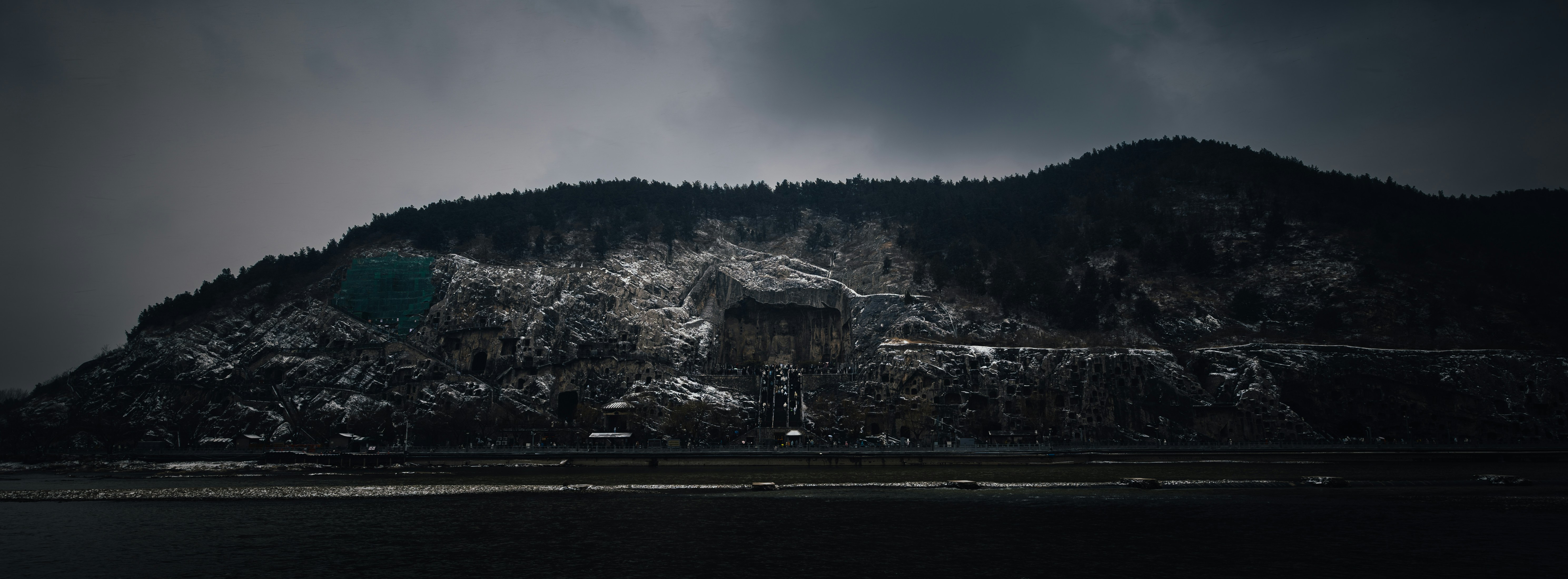 Storm-Weighted Shoreline: Snow-Capped Quarry Under Dark Skies