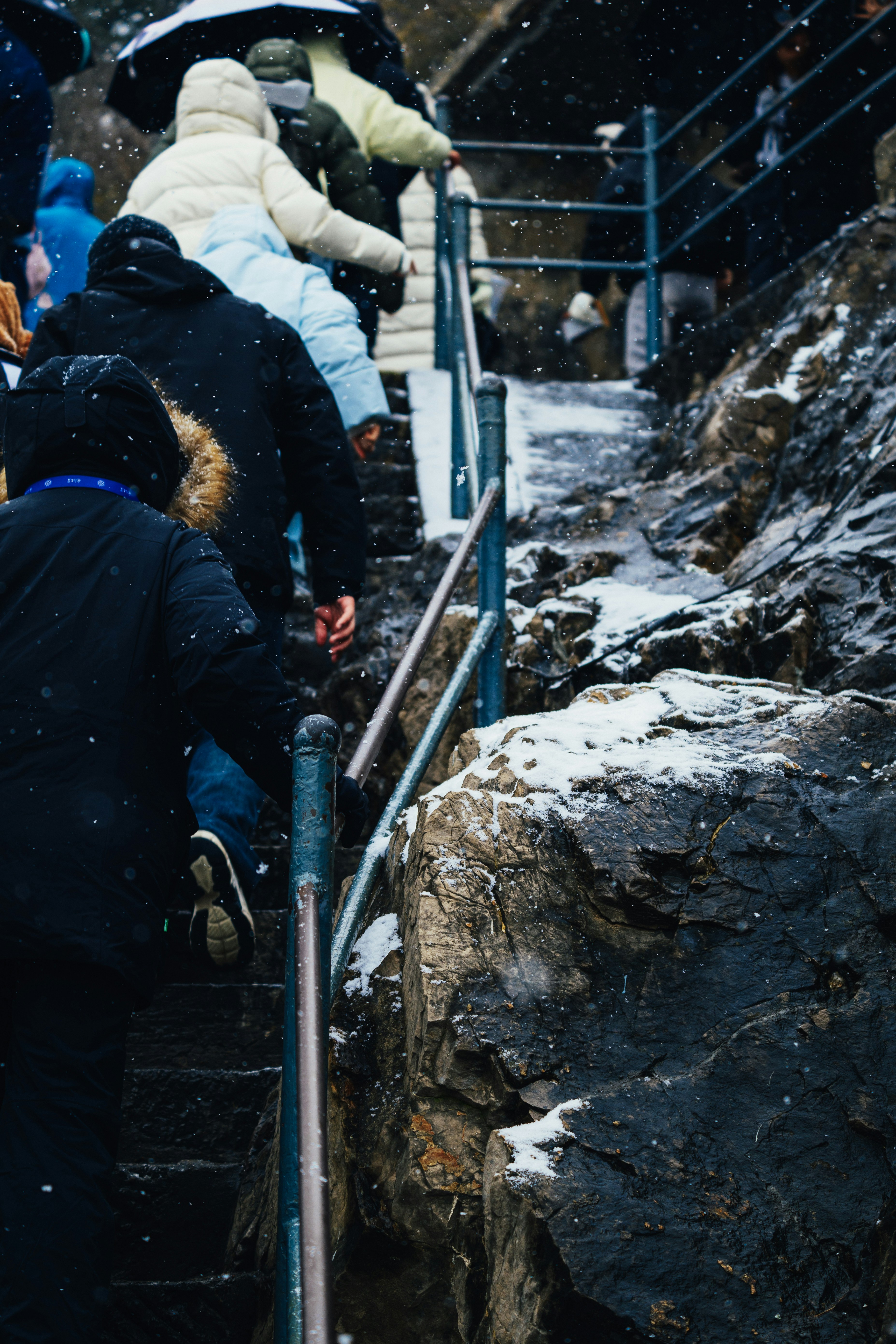 Climbing the winter ascent: a stairway of hikers through snow and rock