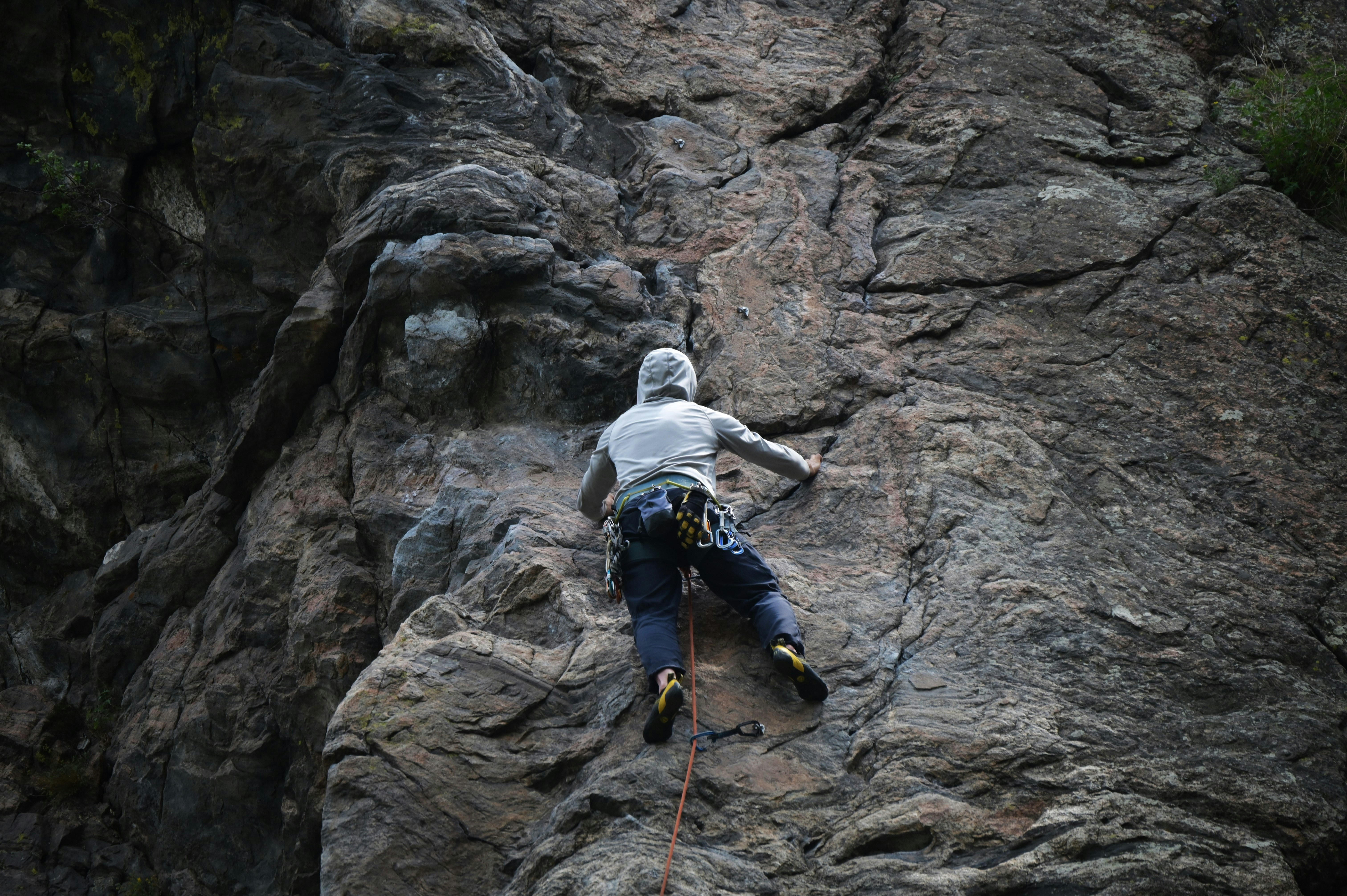 Climber in Focus: gripping ascent along a rugged cliff