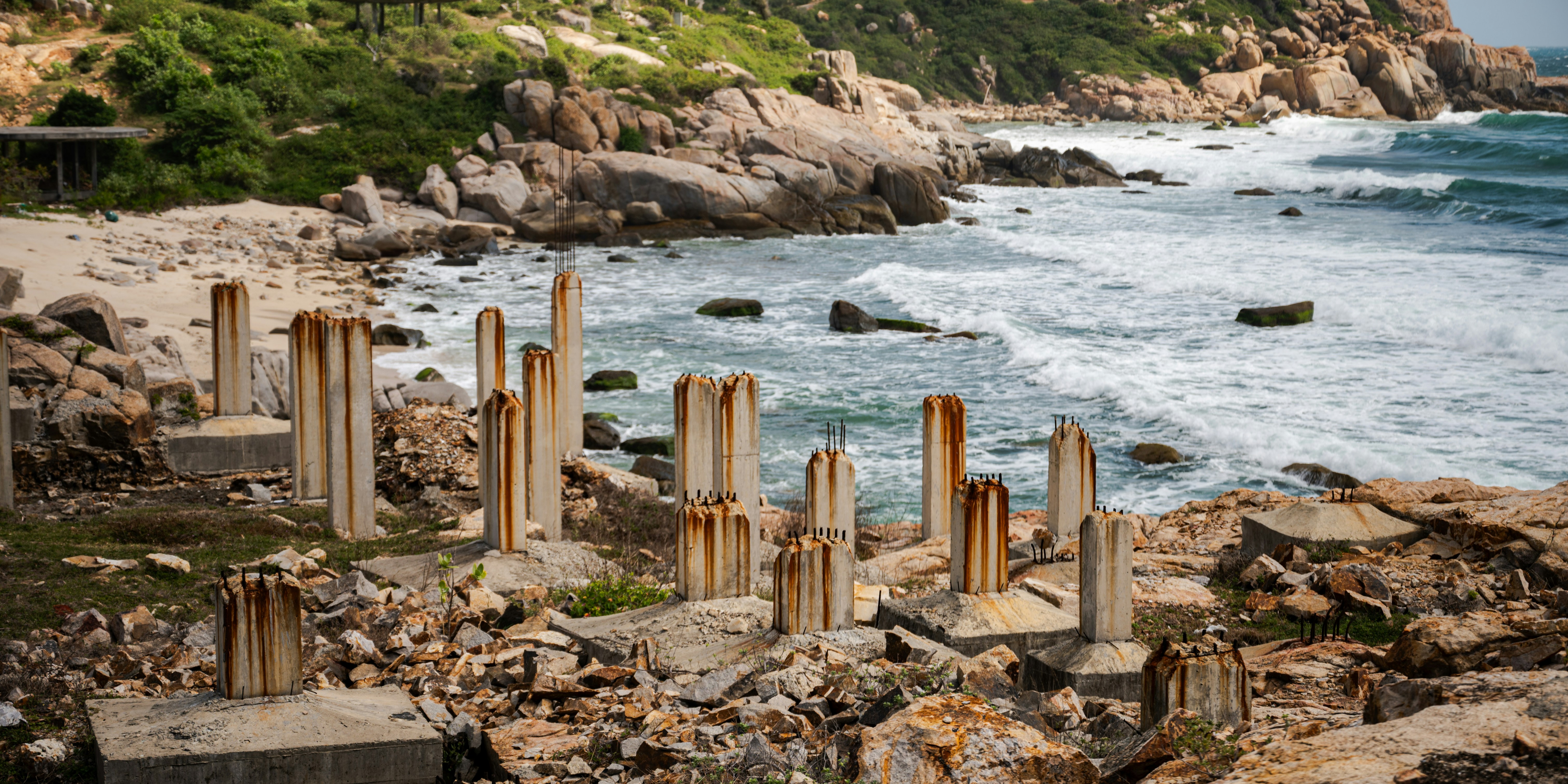 Rusted Cylinders Rising from Shoreline: A Quiet Edge of the Sea