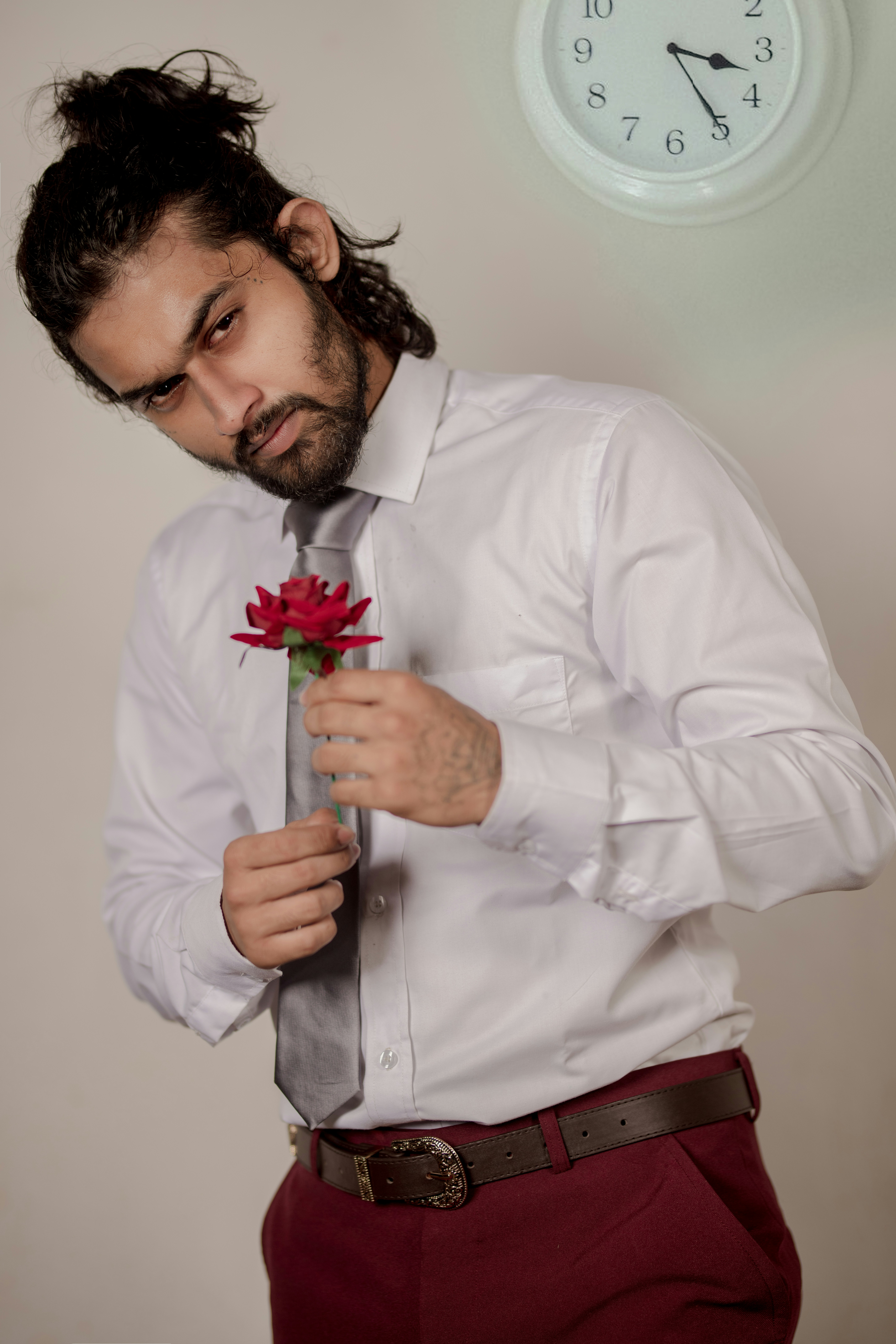 A Quiet Blossom: A Man in White and Burgundy Adjusts Time with a Rose