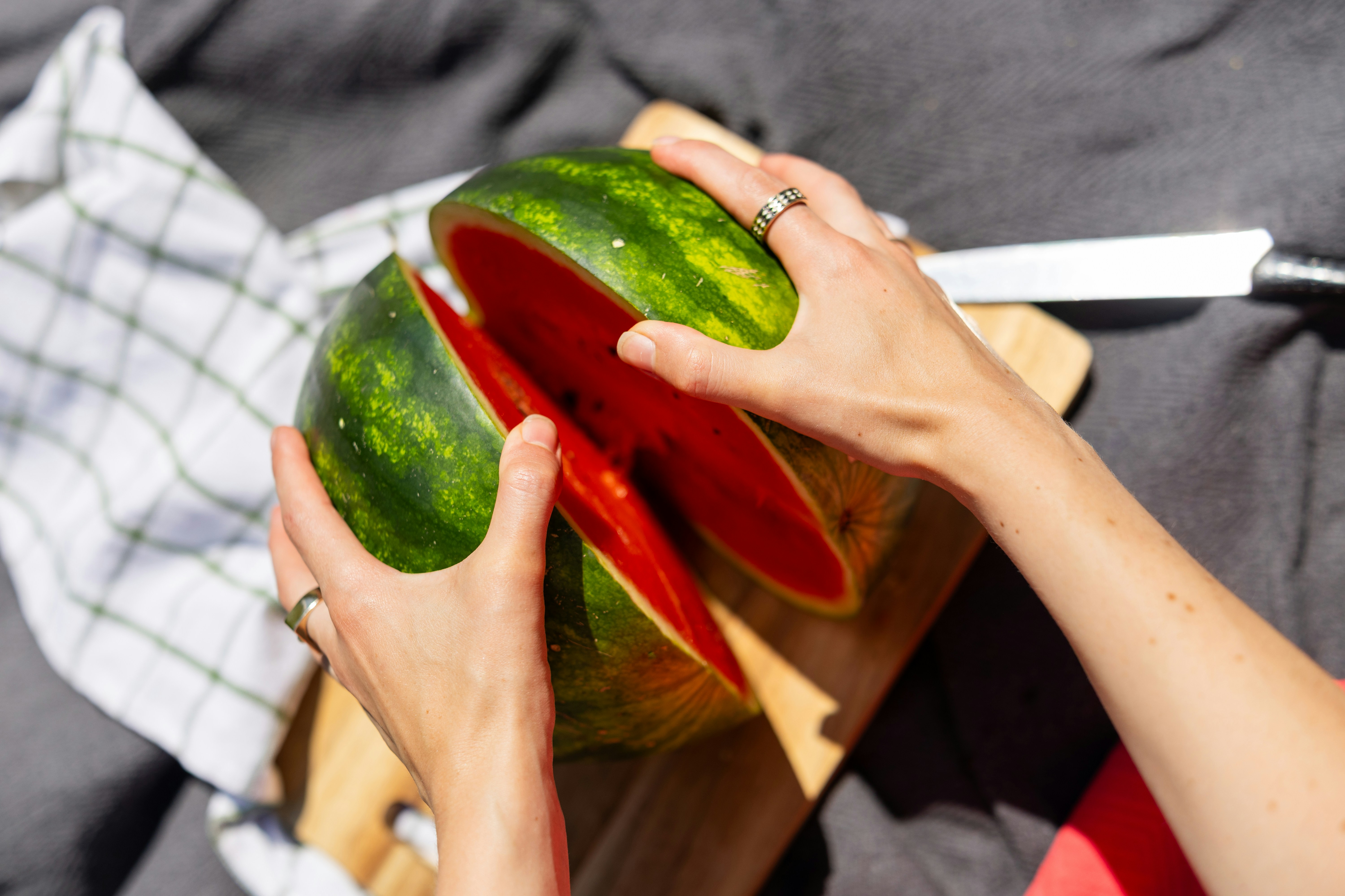 Hands at the Cut: Fresh Watermelon Split on a Wooden Board
