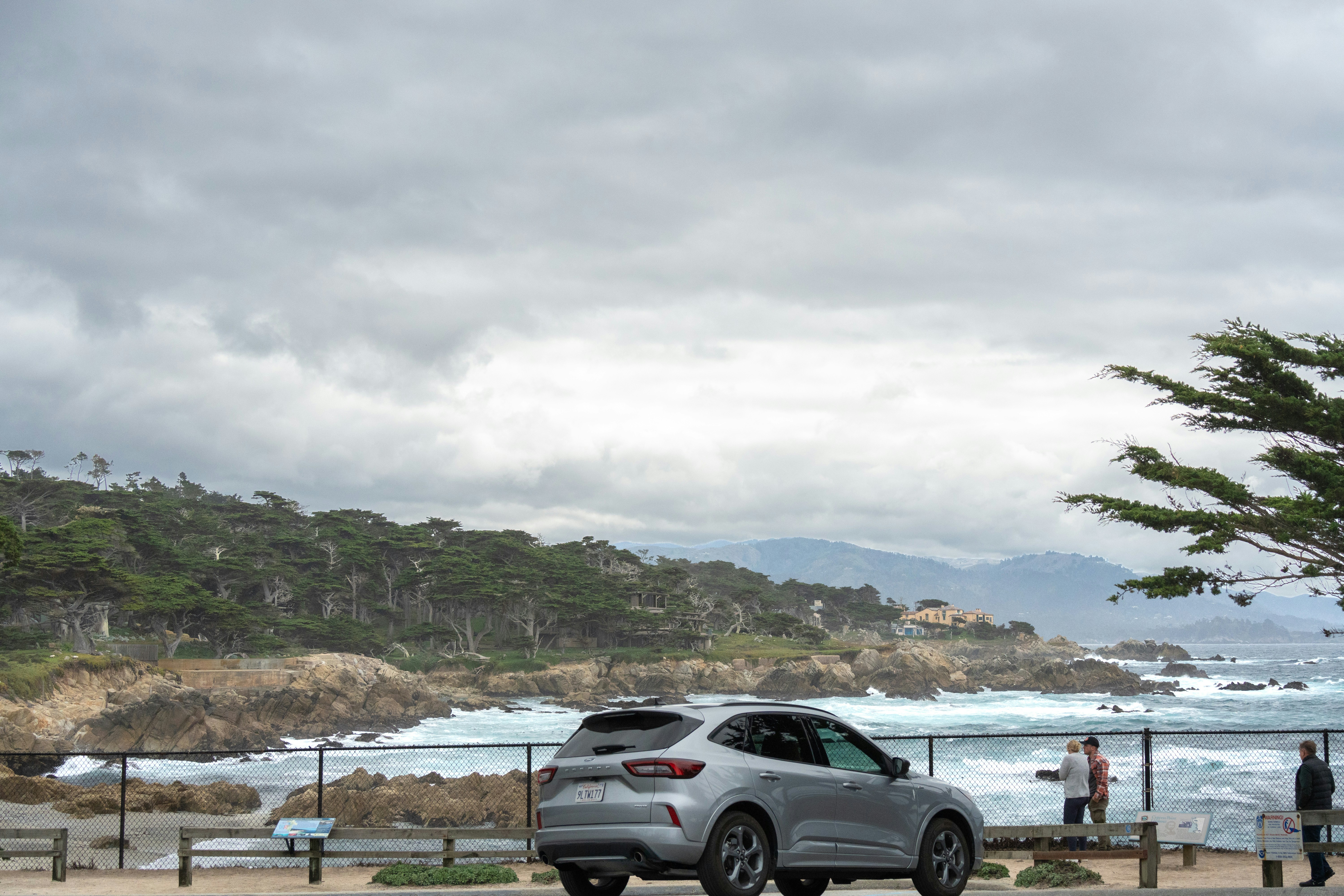 Coastal overlook with a parked SUV near rugged shoreline