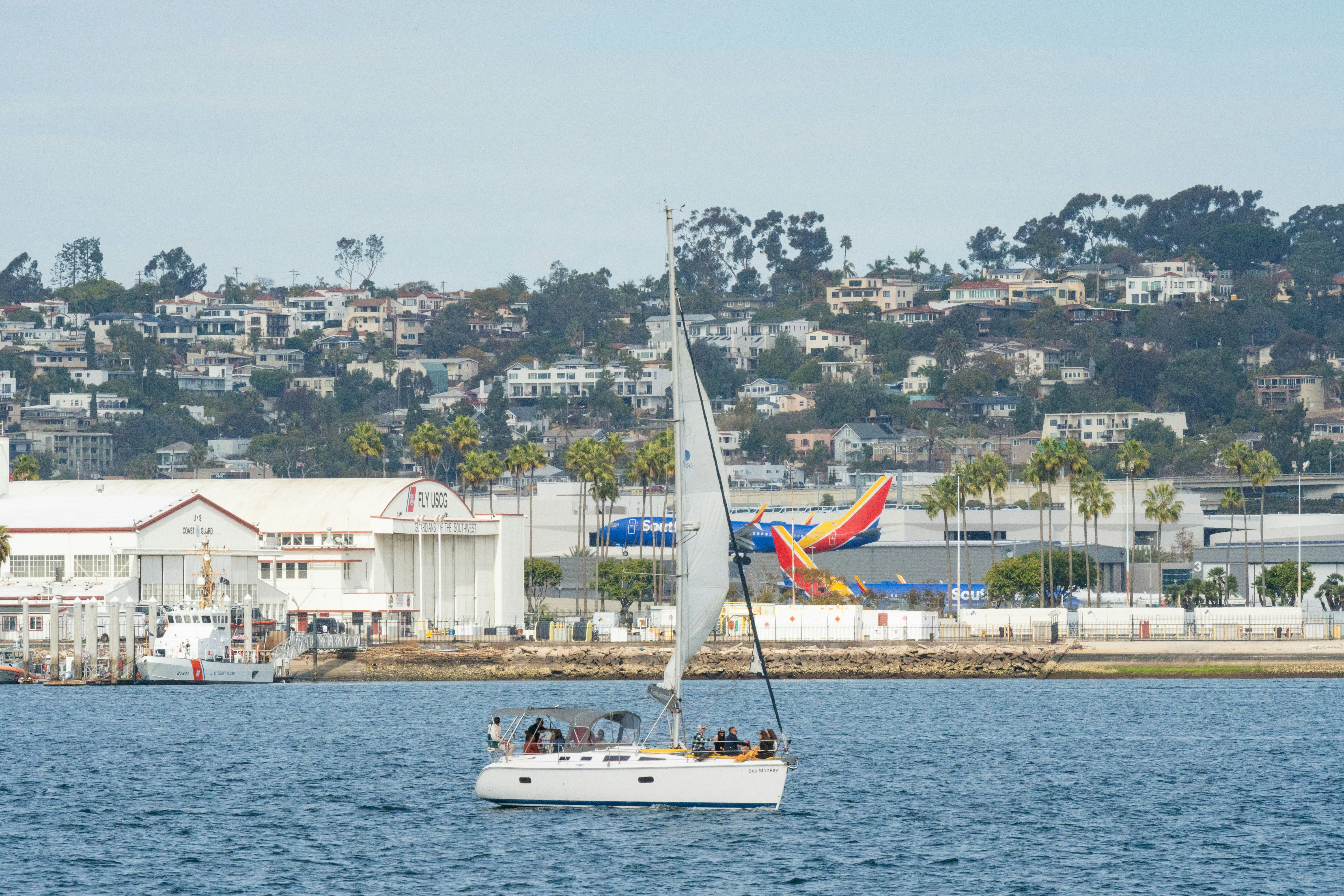 Sailboat Crossing the Blue Harbor with Coastal Town Backdrop