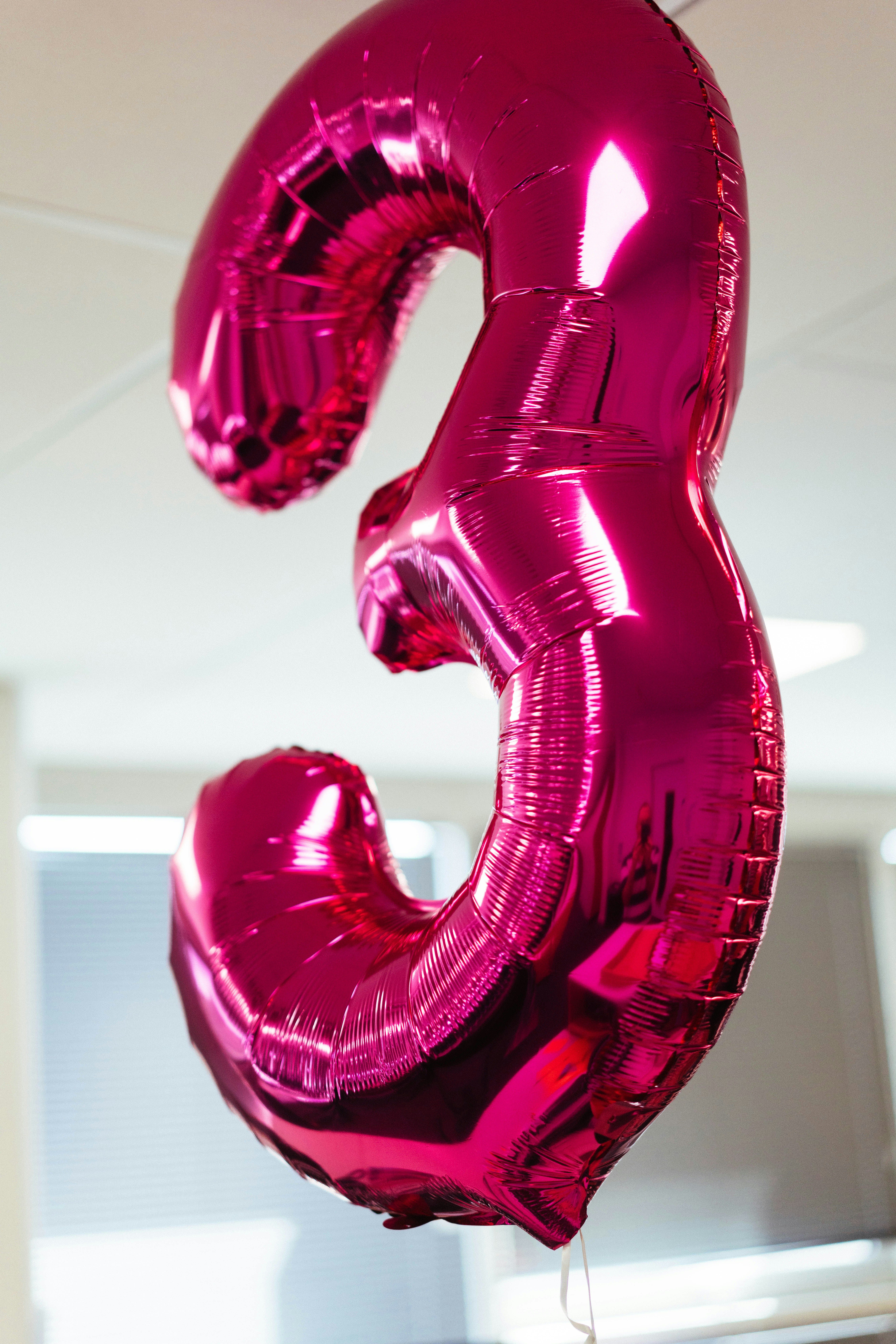Magenta Balloon Glyph: A Close‑Up of a Shiny Curved Letter