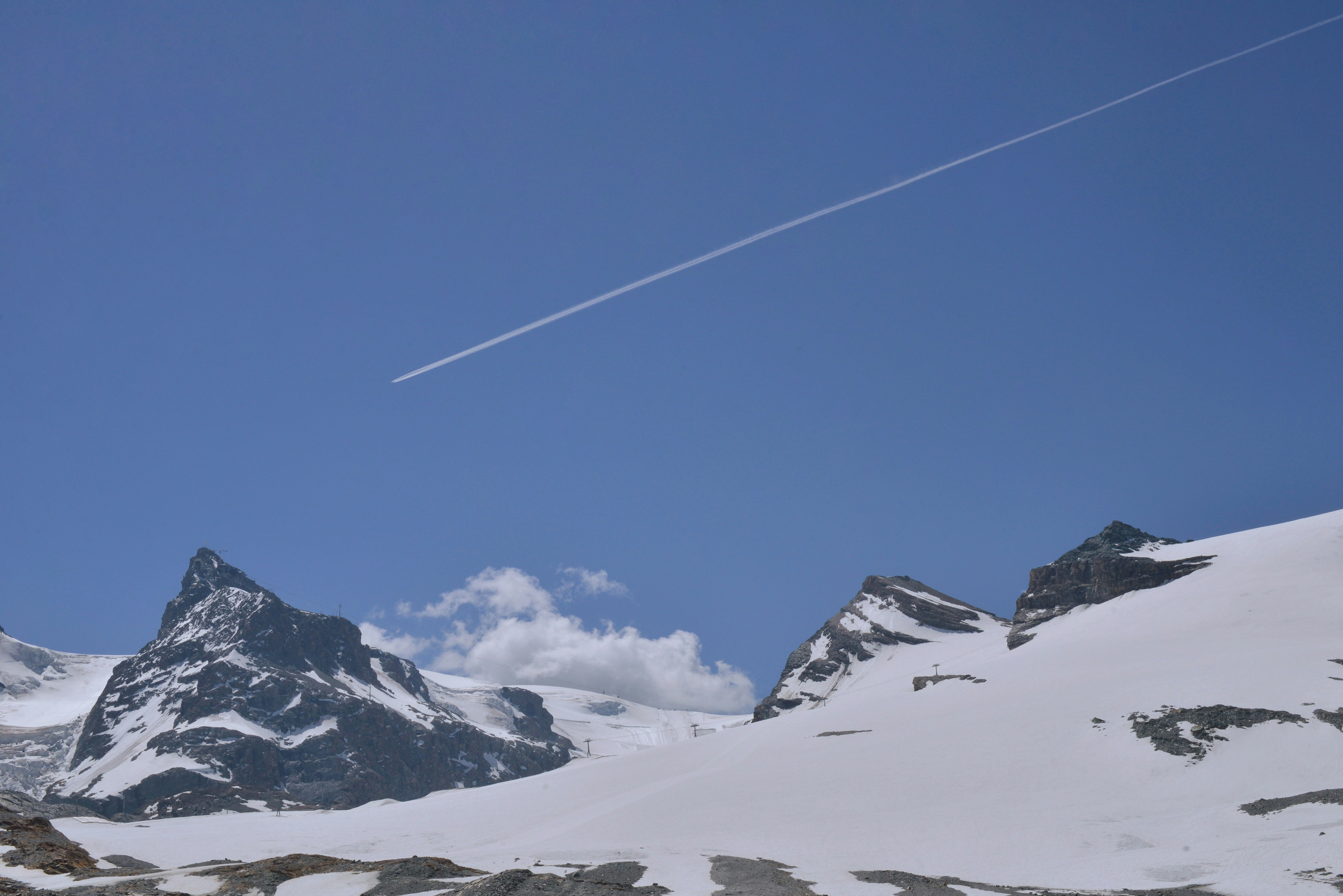 High Alpine Trace: A Contrail Crossing a Snowbound Spine