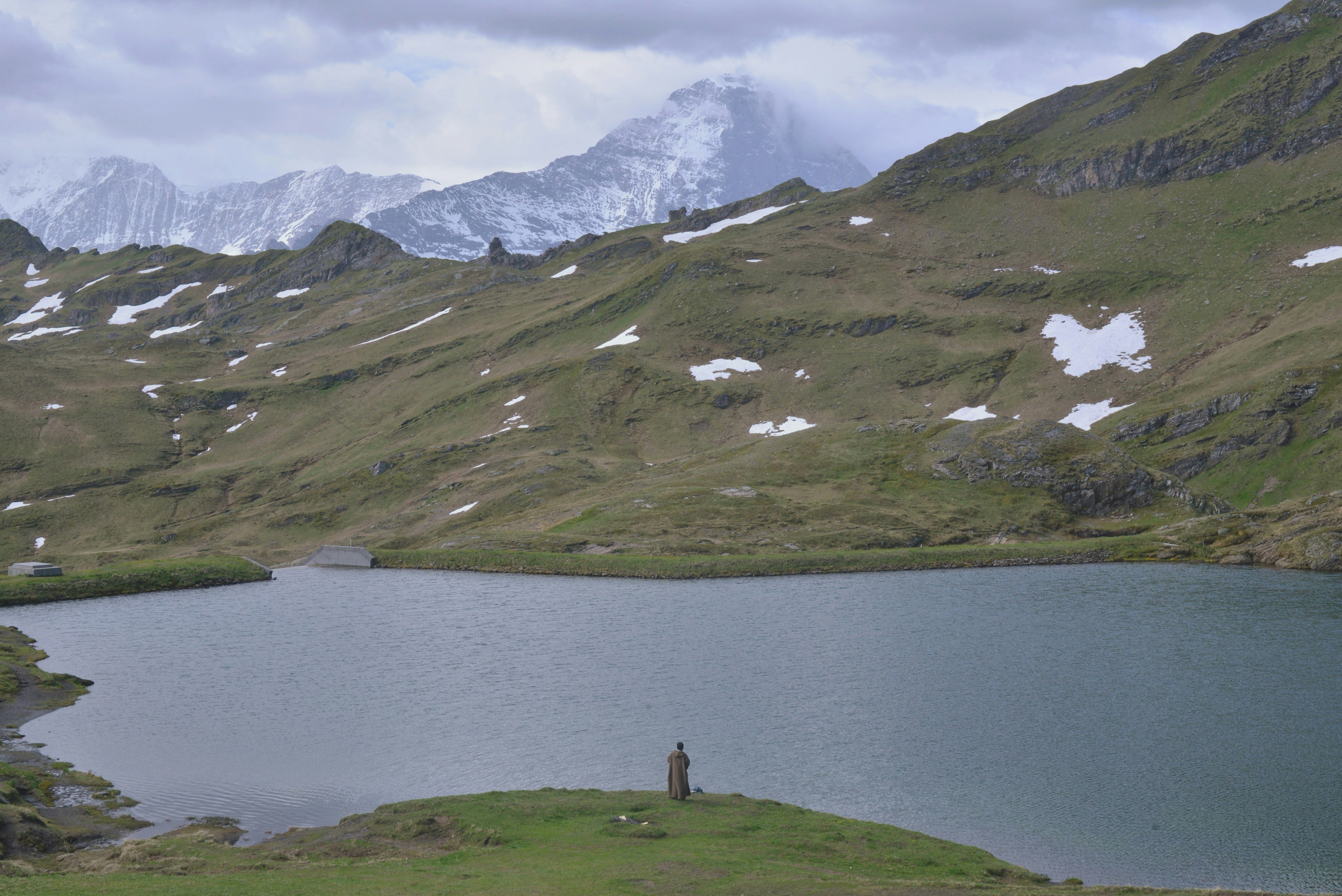 Single Traveler at the Lake's Edge Beneath Snow-Capped Prominence