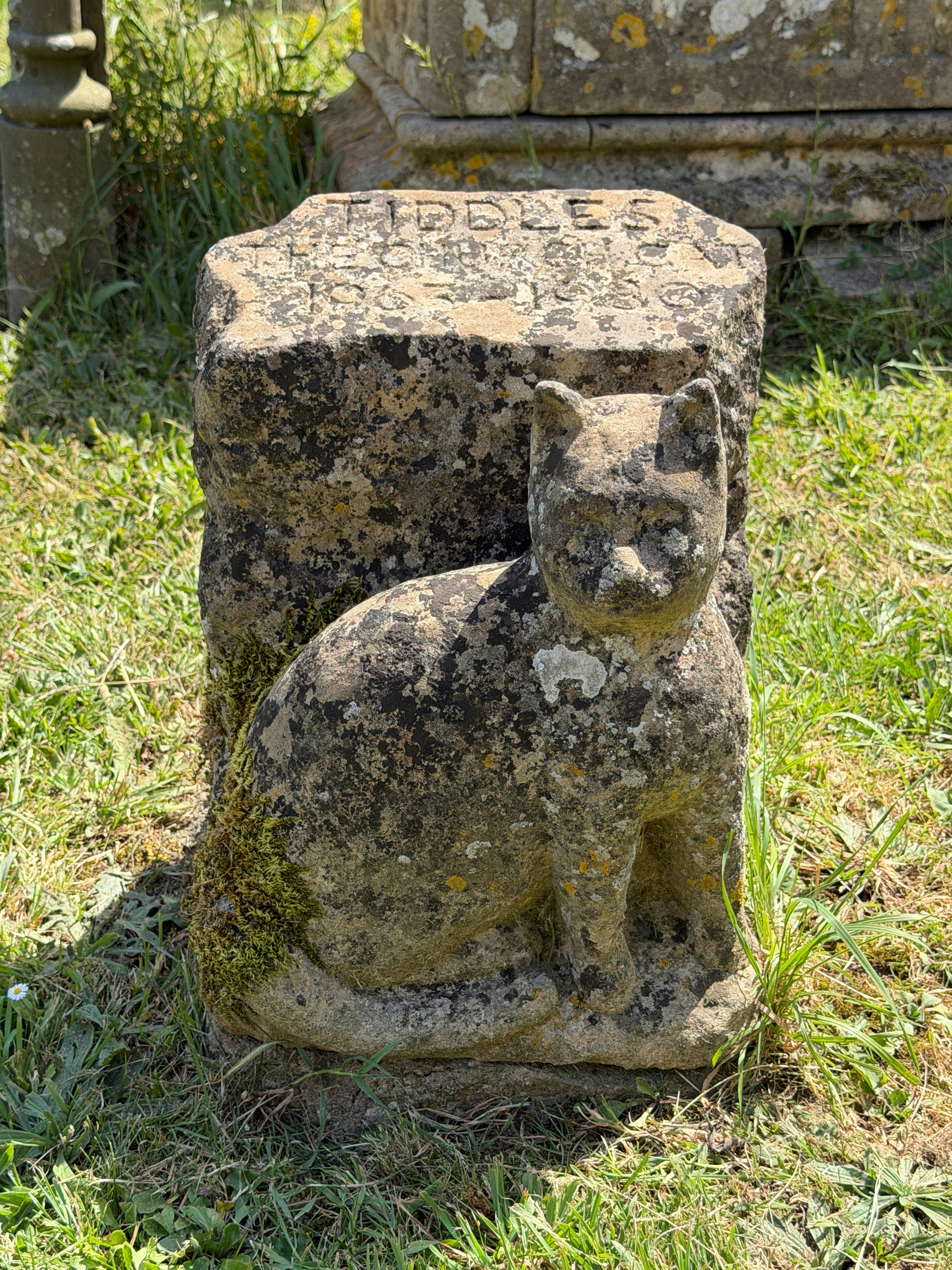 Lichen-Scaled Sentinel: A Weathered Cat Sculpture in a Graveyard Garden