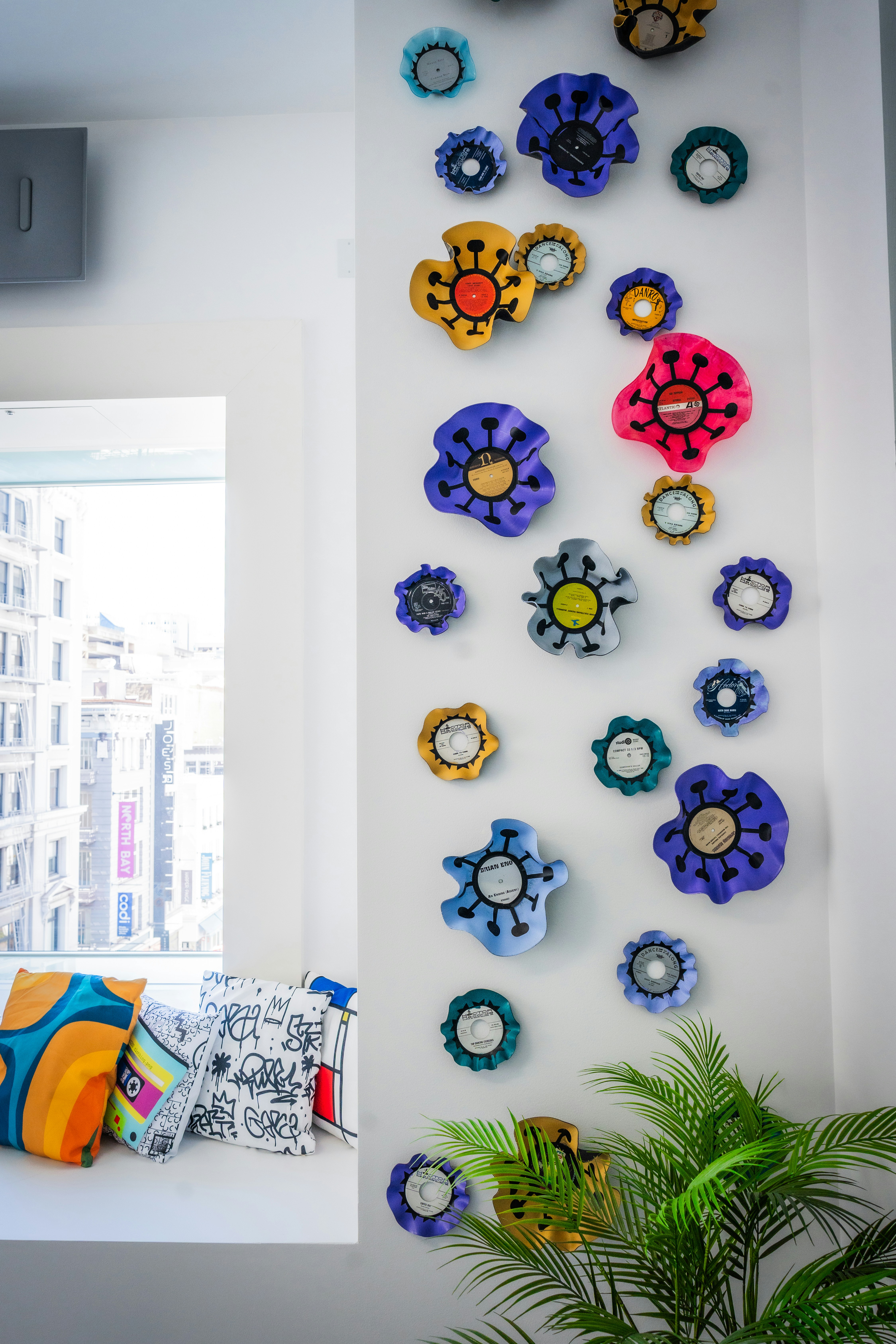 Colorful Wall of Time: Circular Art Pieces Flowing Down the Gallery Column