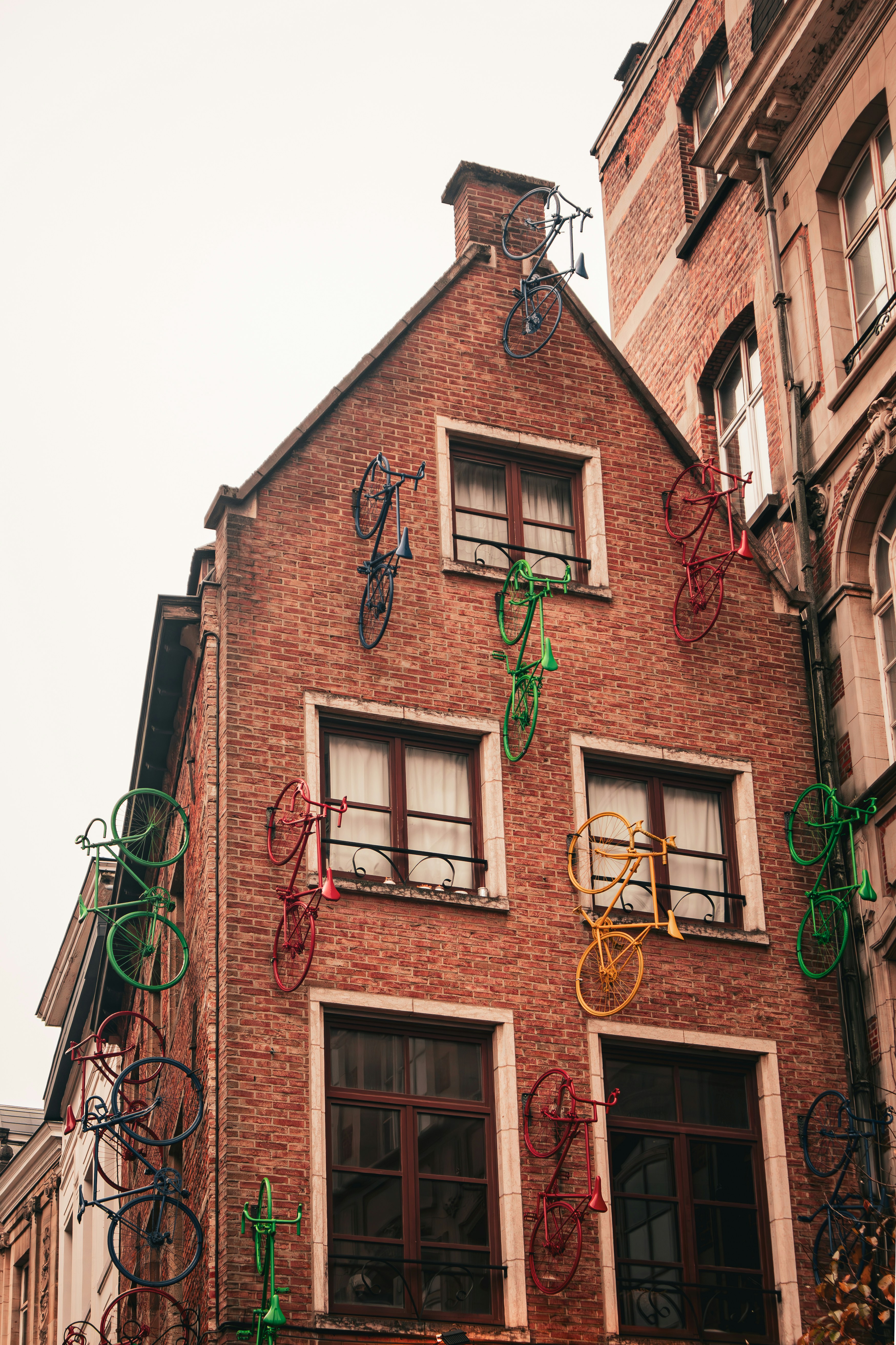 Colorful Bicycle Sculpture Drape over an Urban Brick Facade
