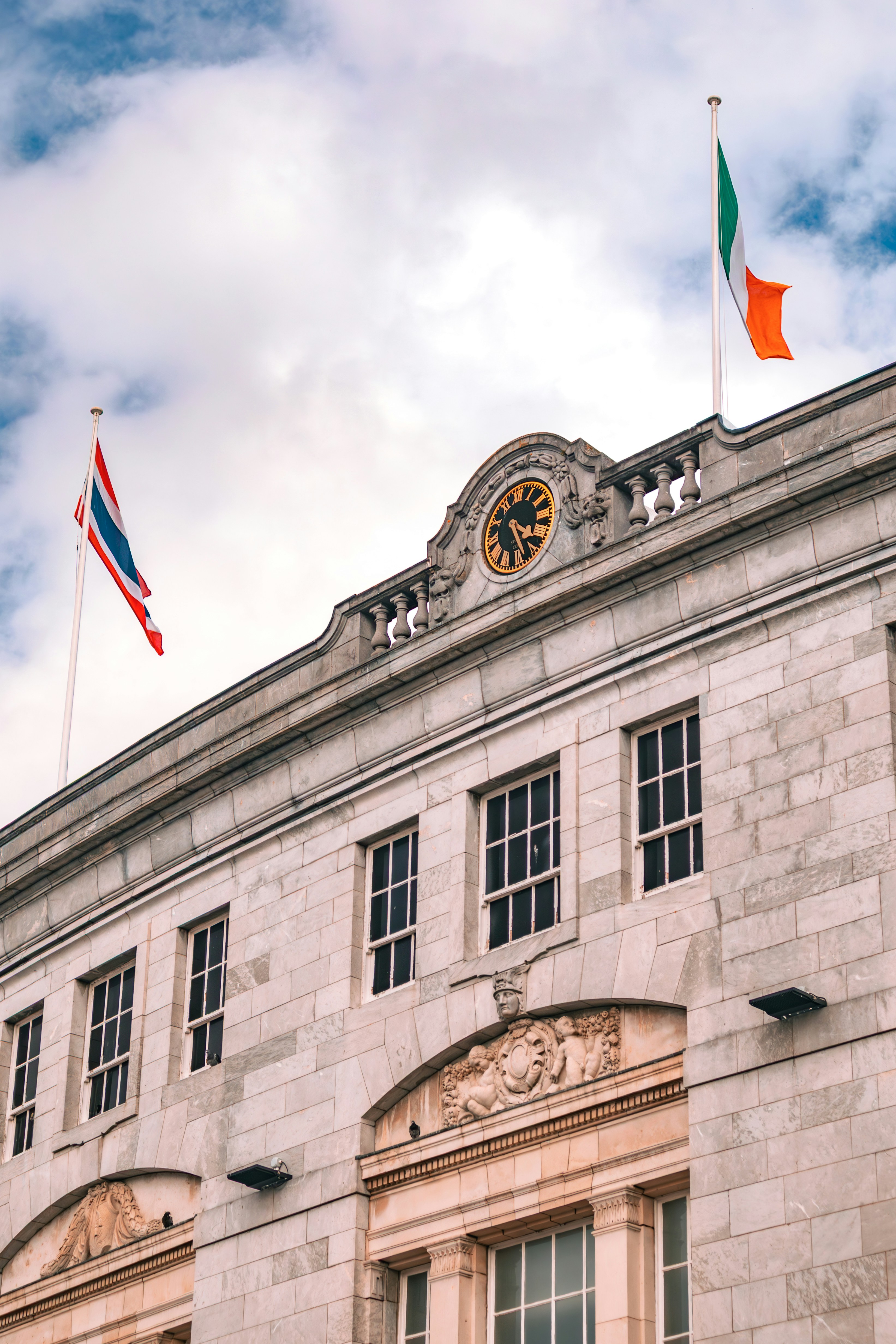 Flagged Facade: A Historic Clock Overlooking Flagpoles and Stonework