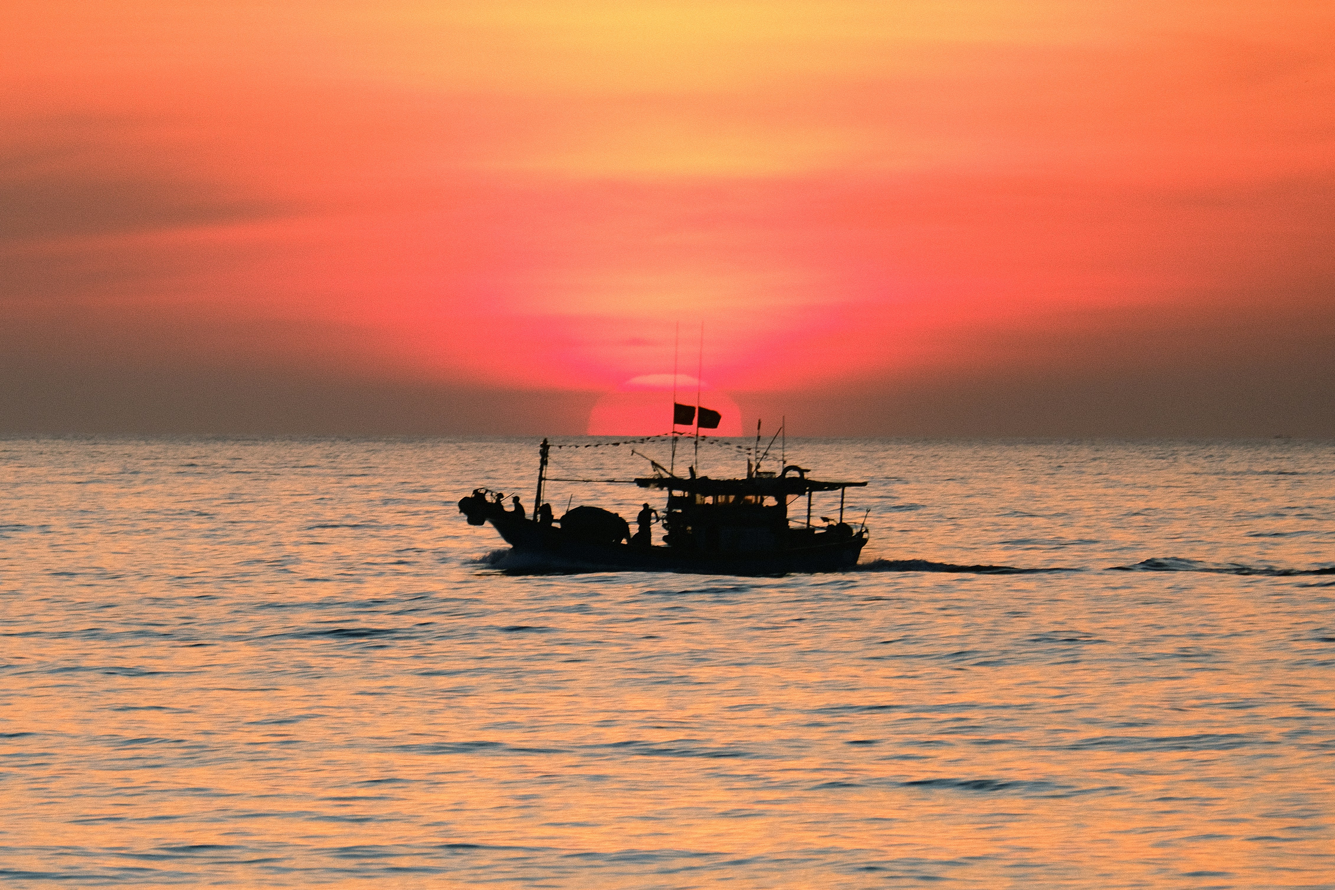 Silhouetted Fishing Vessel Against a Coral Sunset