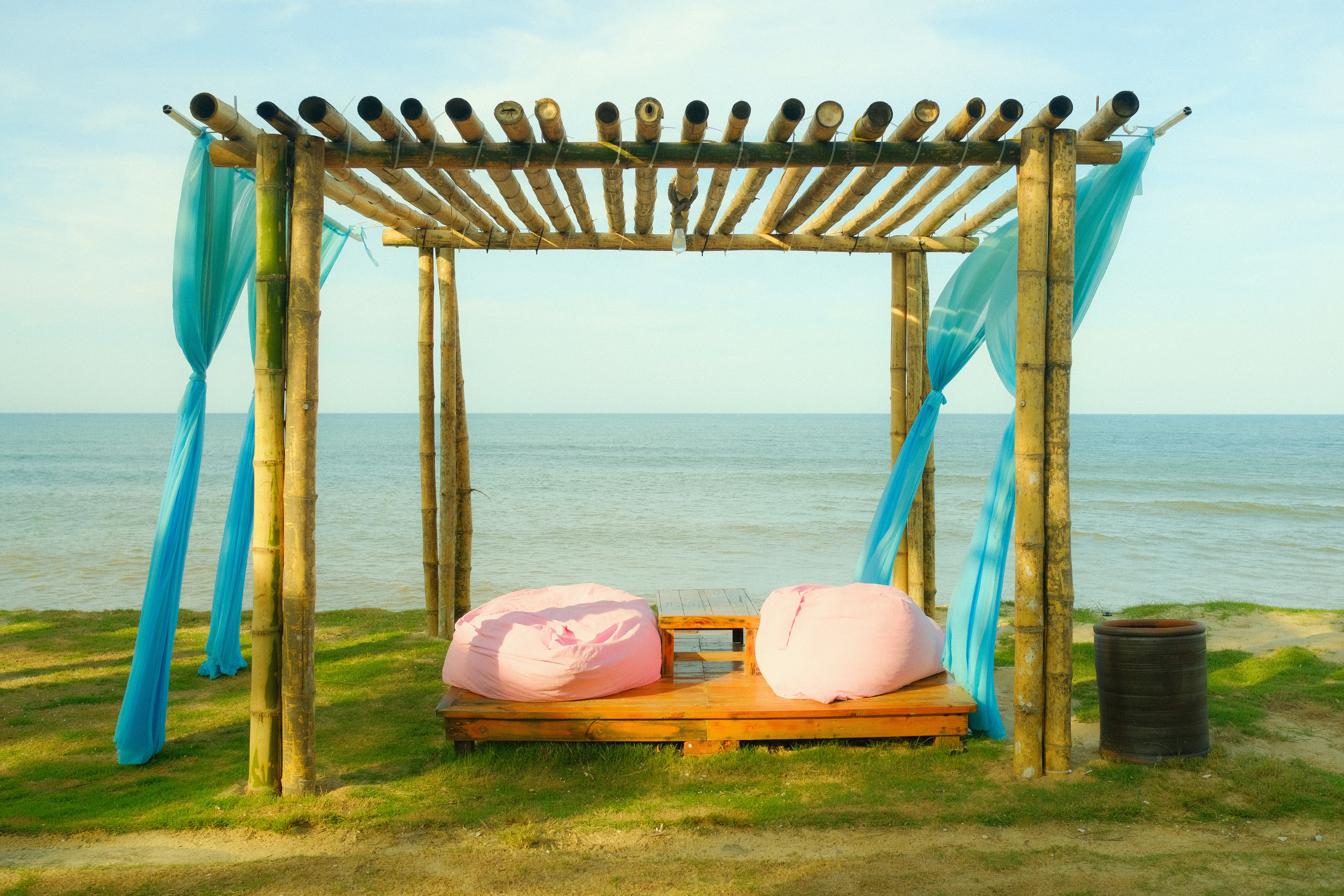 Beach Pergola with Soft Seating Beneath Turquoise Drapes