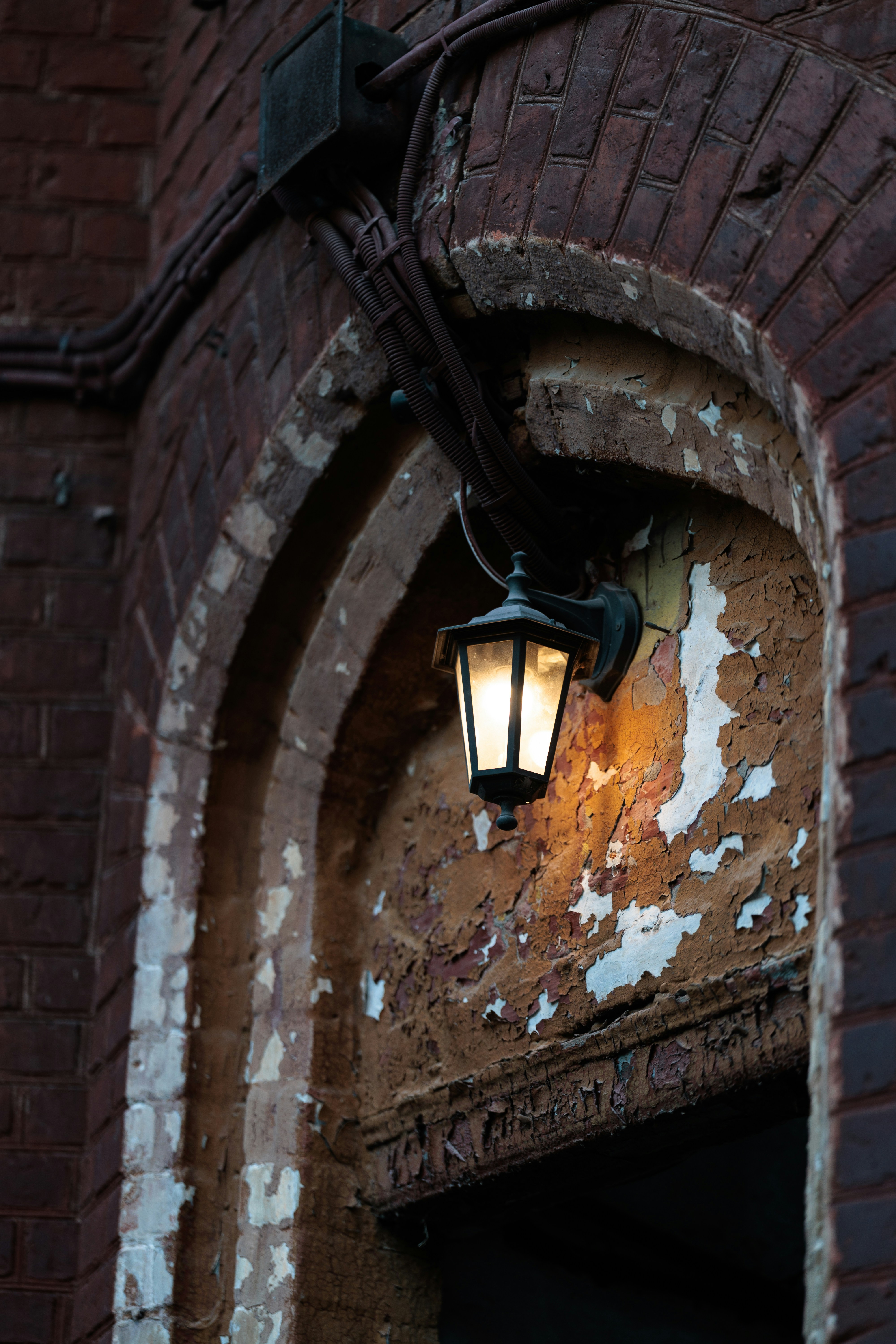 A Lantern in the Arch: Warm Light Against Weathered Brick
