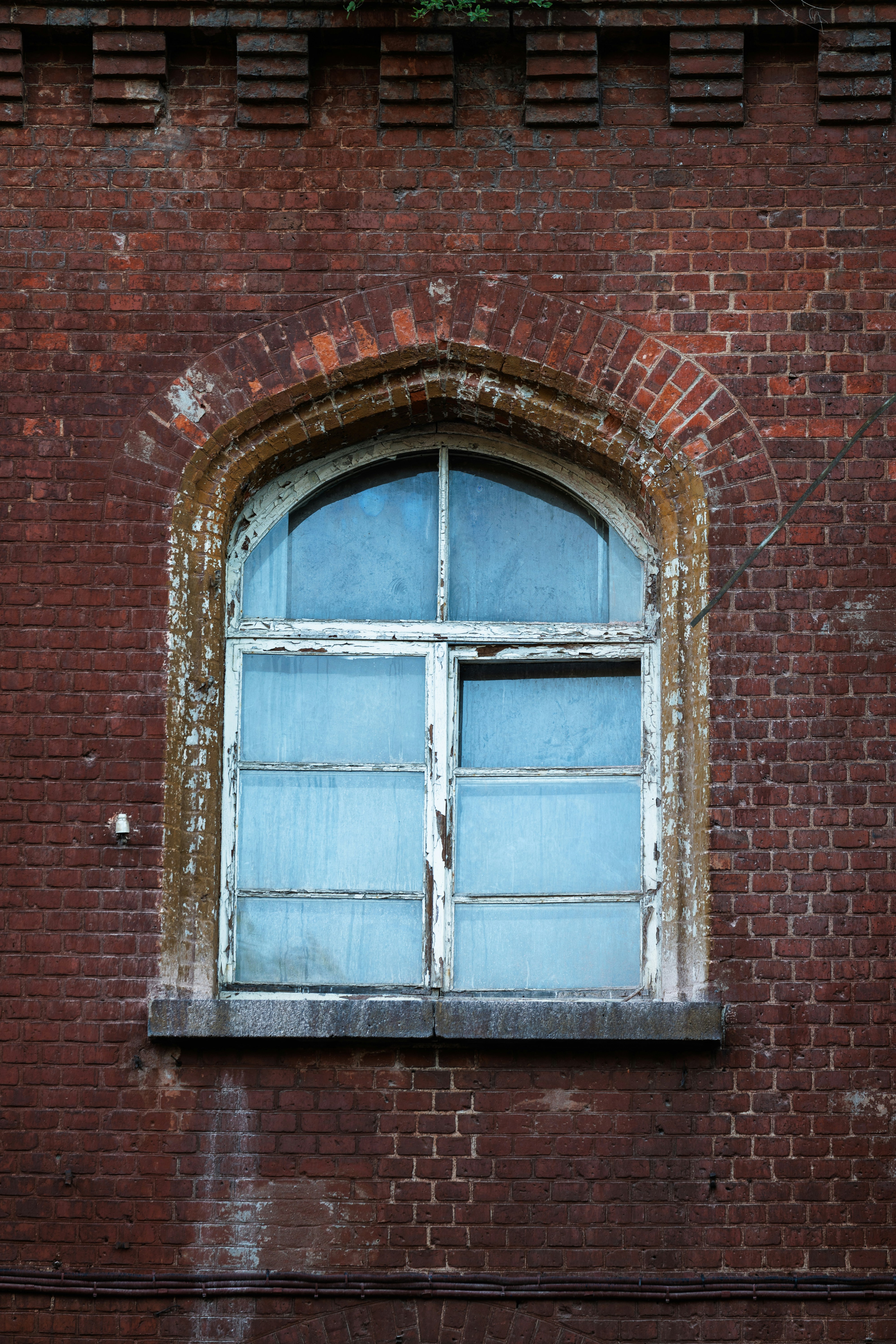 Weathered Arch Window in a Red Brick Facade