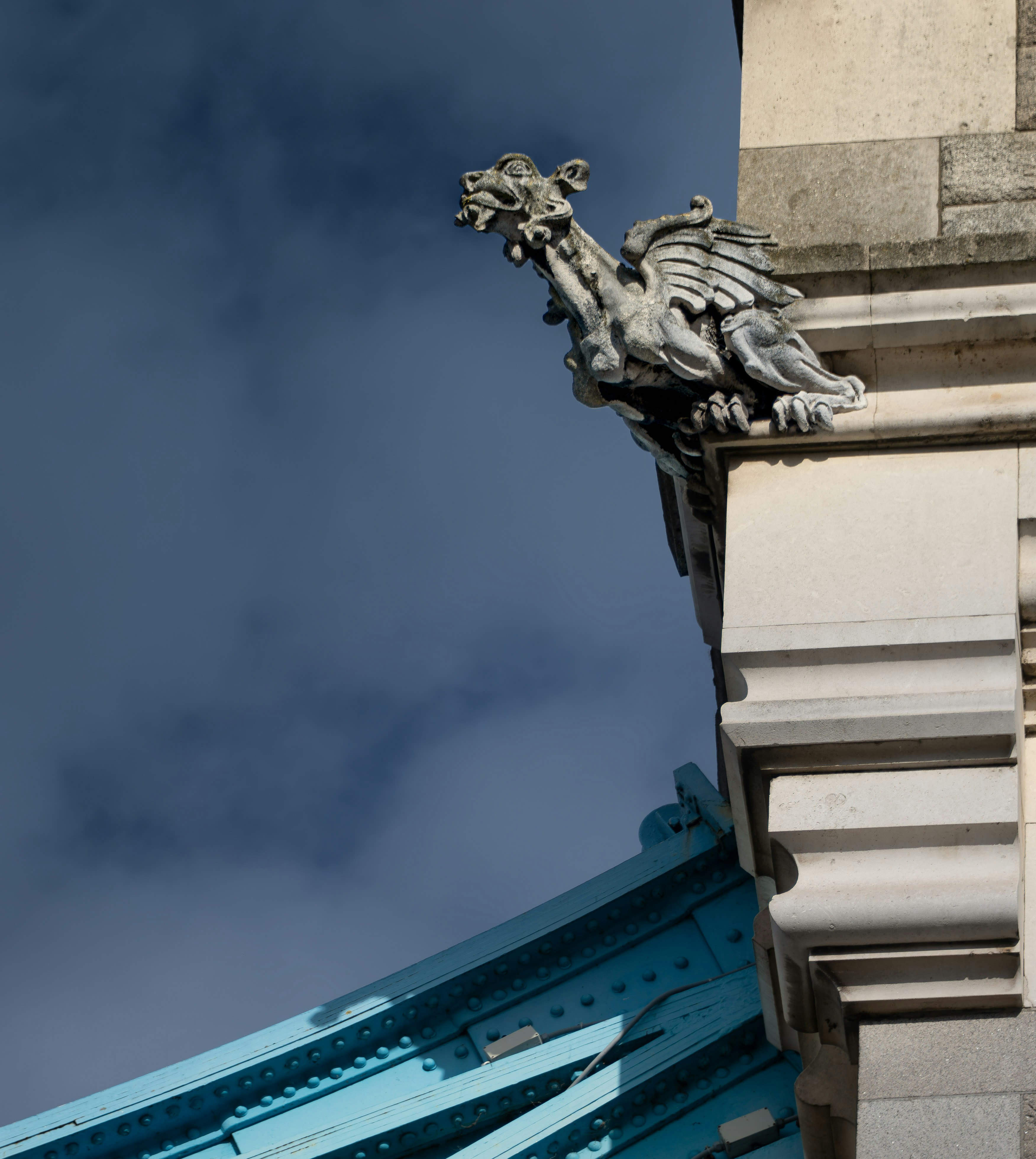 Stone Griffin Overlook: Corner Sculpture Against a Blue Gable