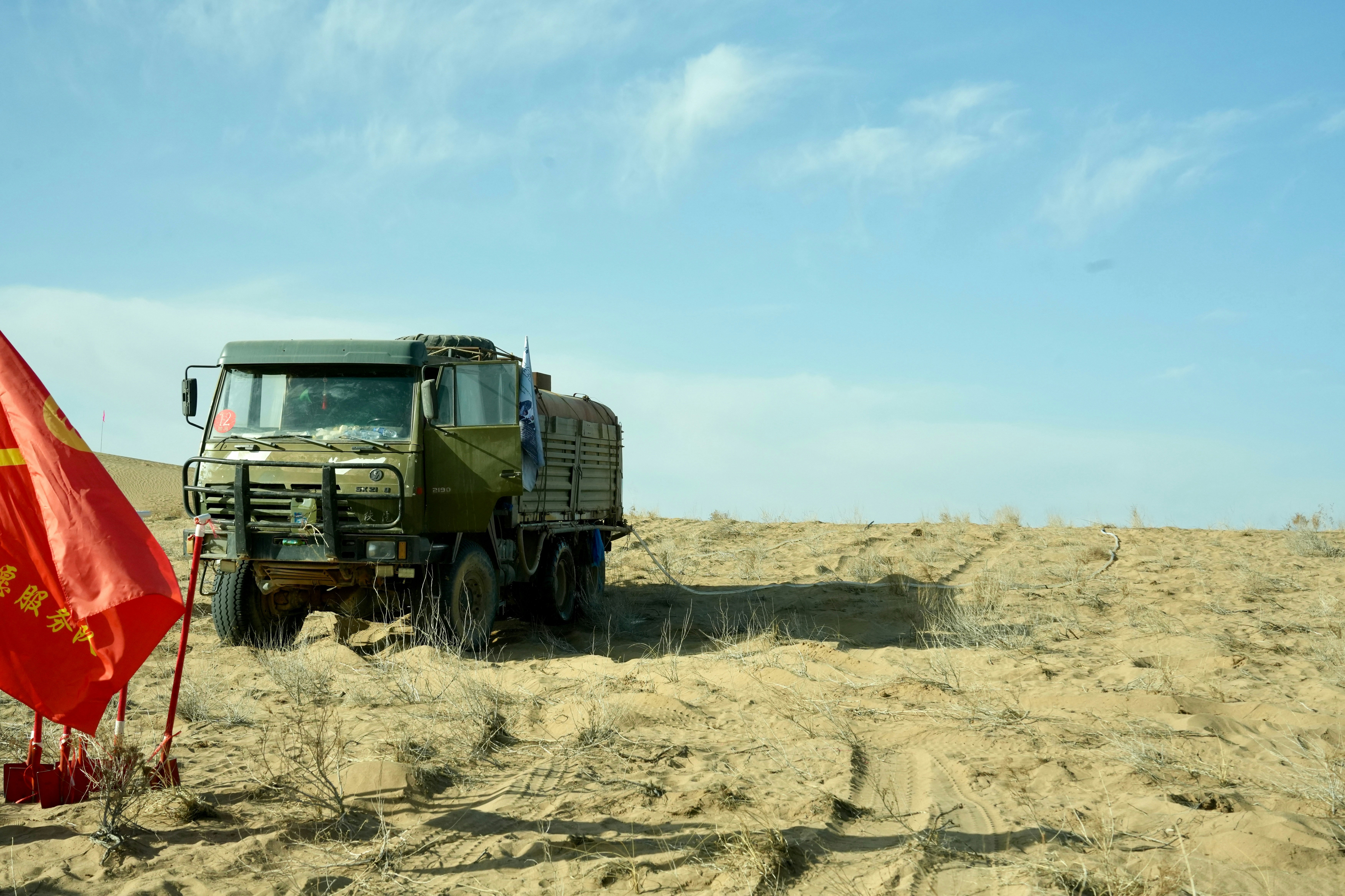 Red Flag and Rutted Tracks: A Military Truck in a Dusty Frontier