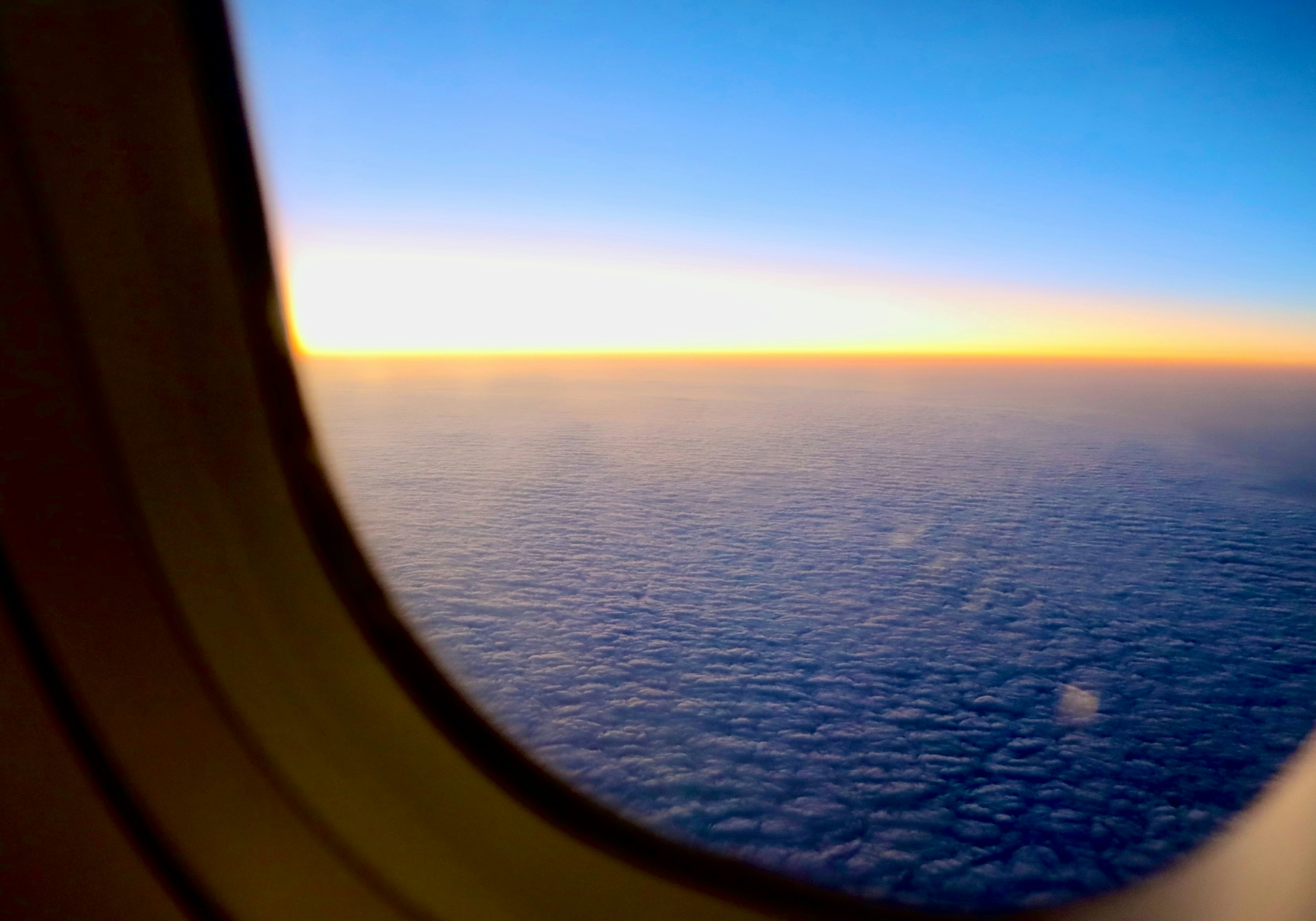 Golden sunset over the ocean from an airplane window.