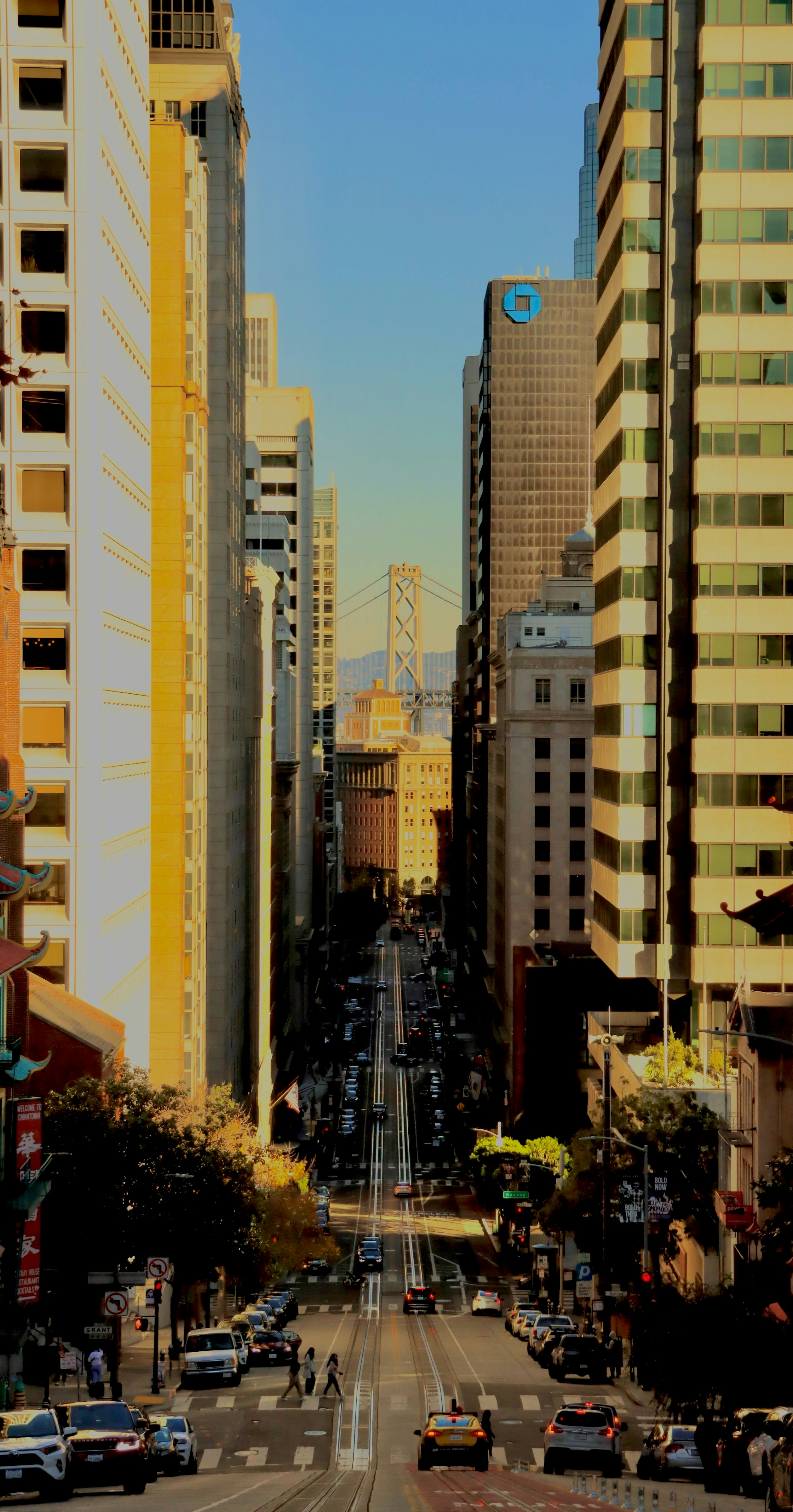 Golden Hour Through the Canyon: A City Street Narrows to a Distant Bridge