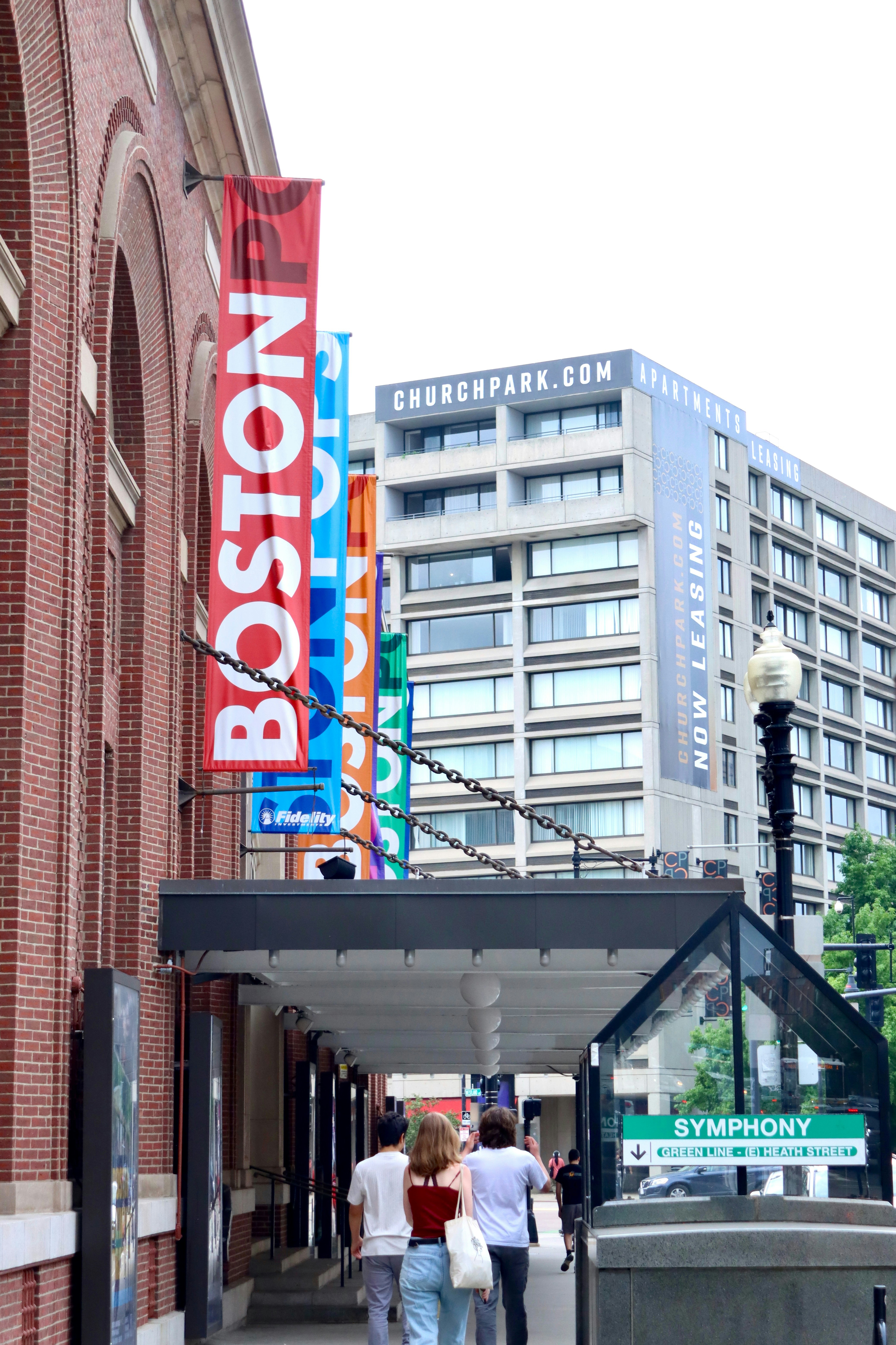 City Street Banner Dance: People Walk Beneath Bright Flags Near a Brick Building