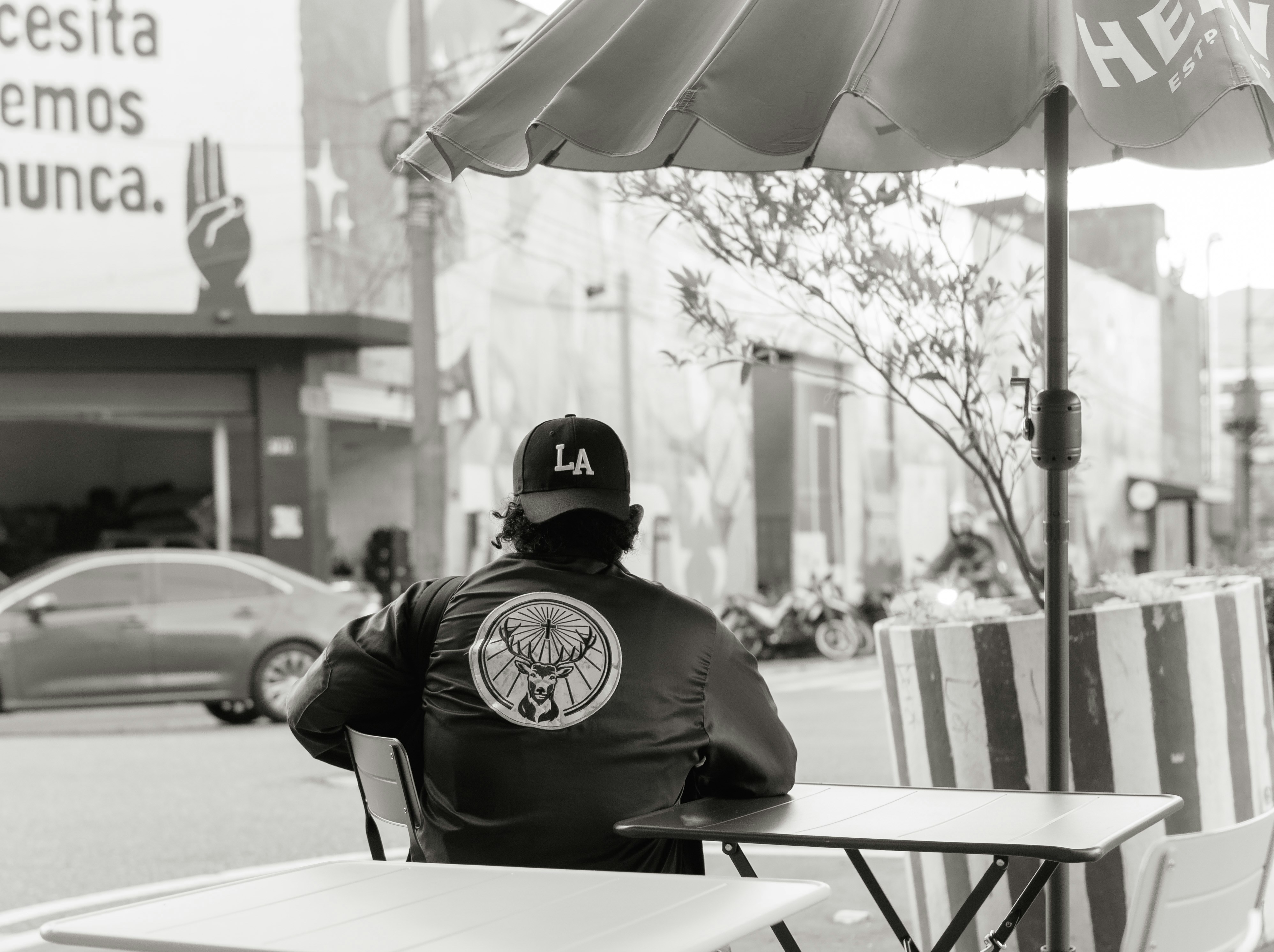 Backside of a lounge: a jacketed rider faces the street from a cafe setting