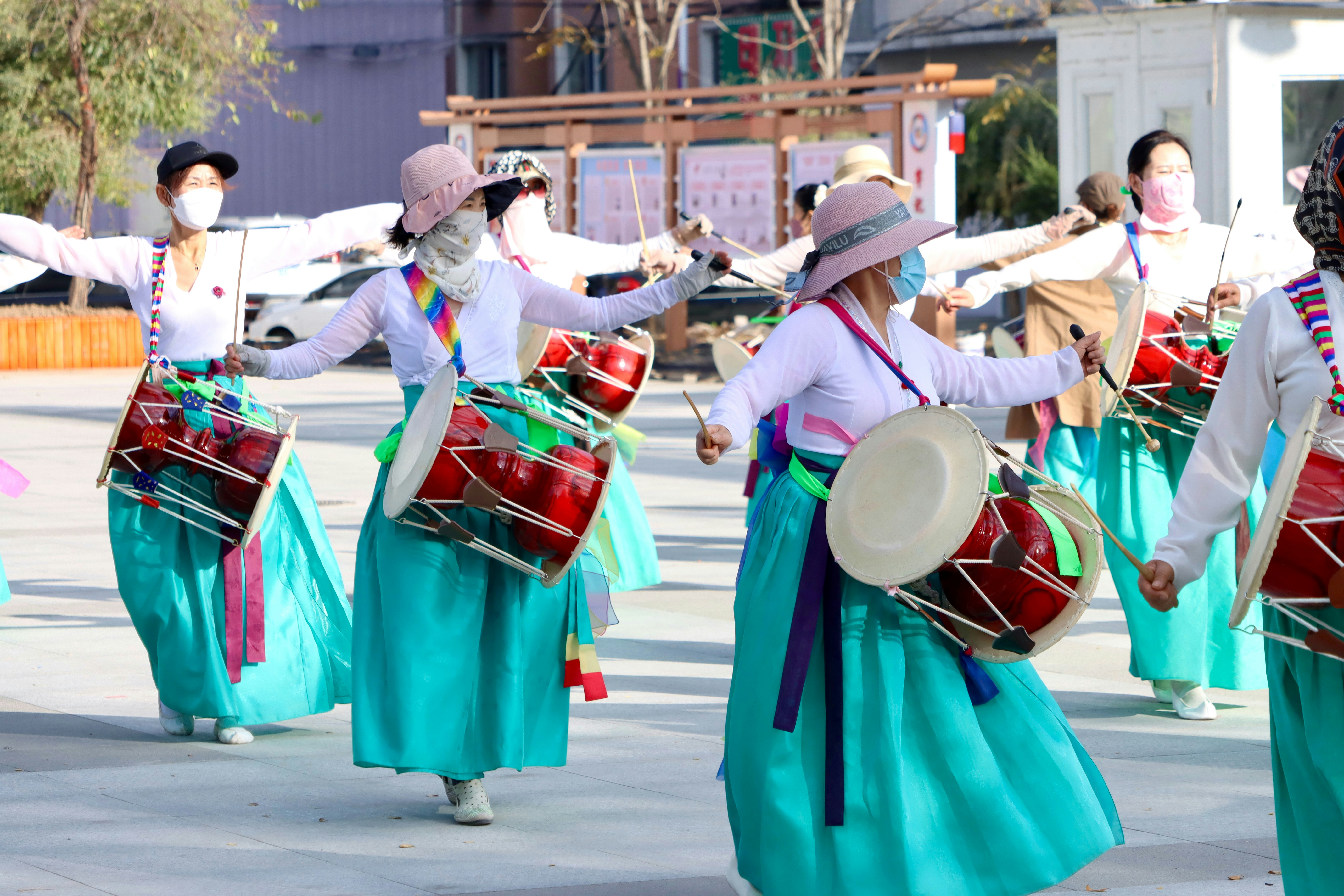 Drumming parade in turquoise skirts and sun hats