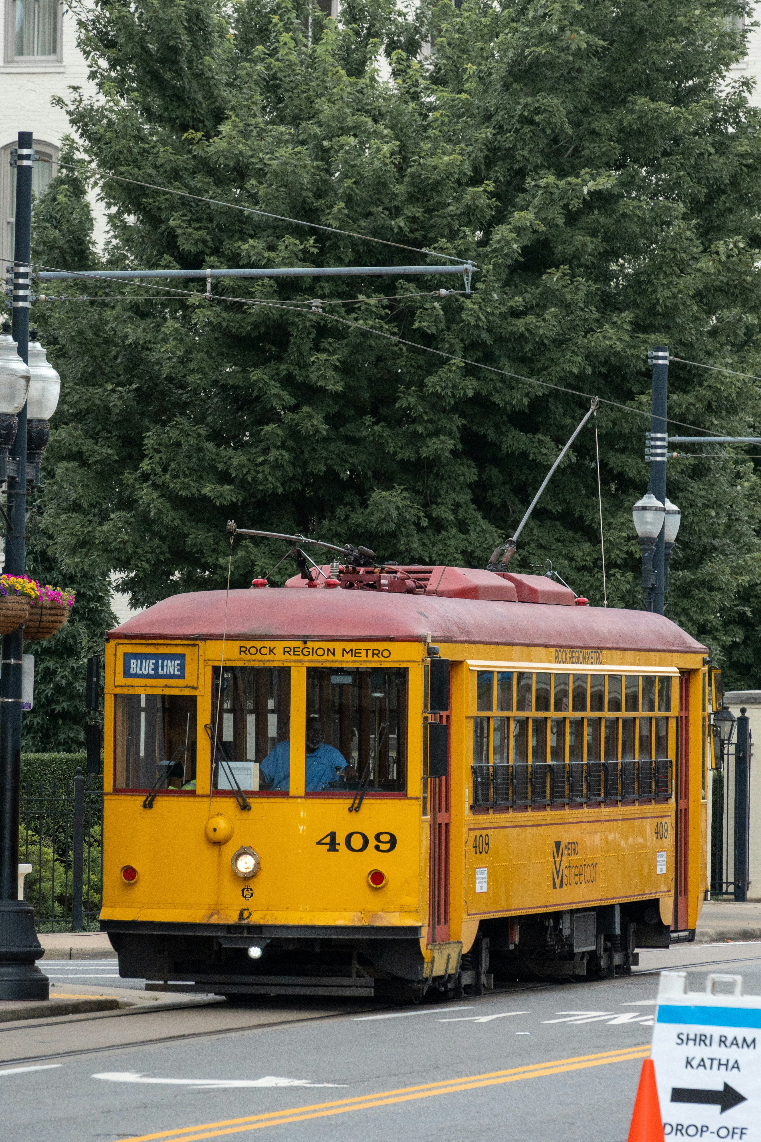Yellow Streetcar on a City Street Under a Green Canopy