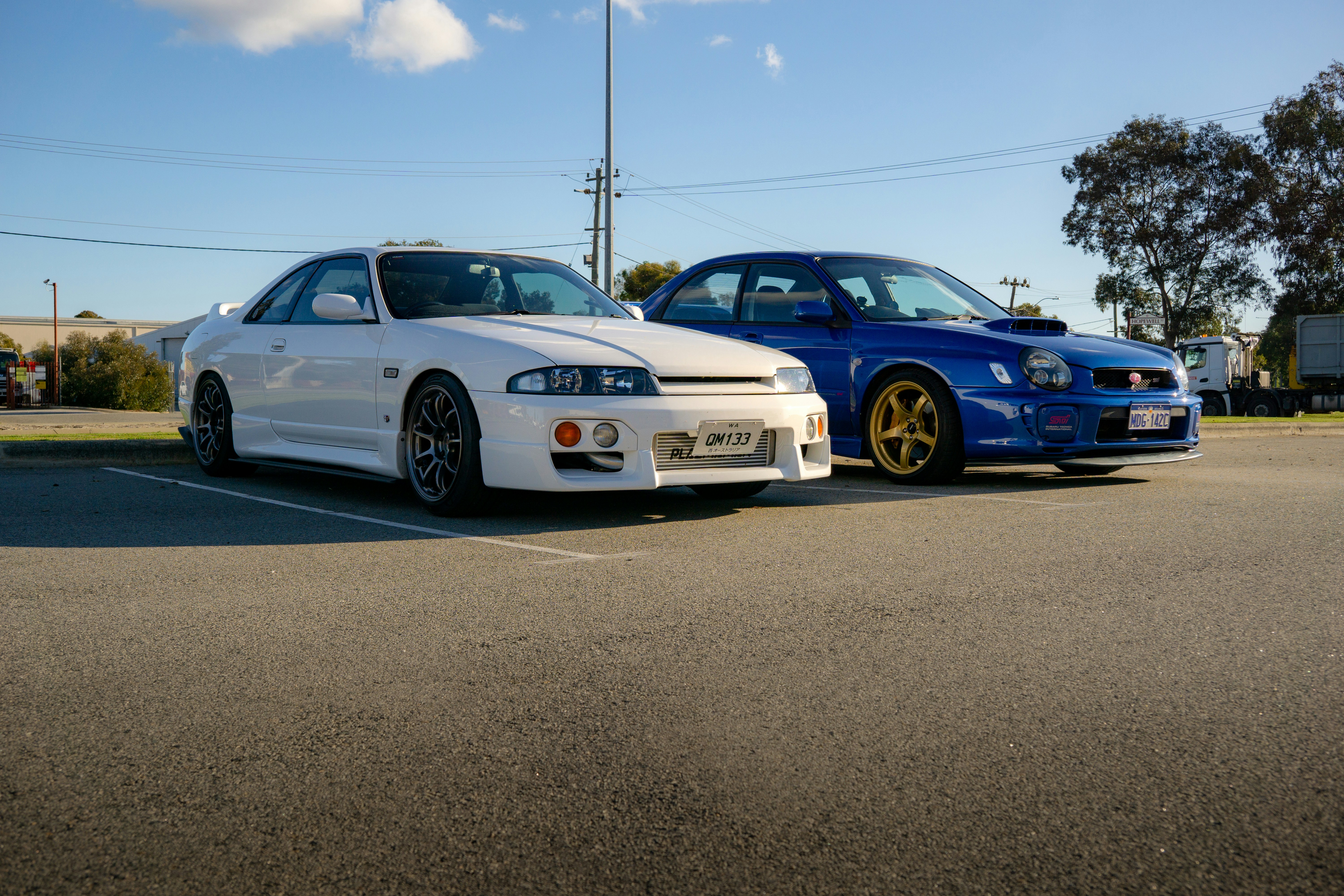 Two Skyline Gliders: White and Blue Sports Cars Rest in Evening Light