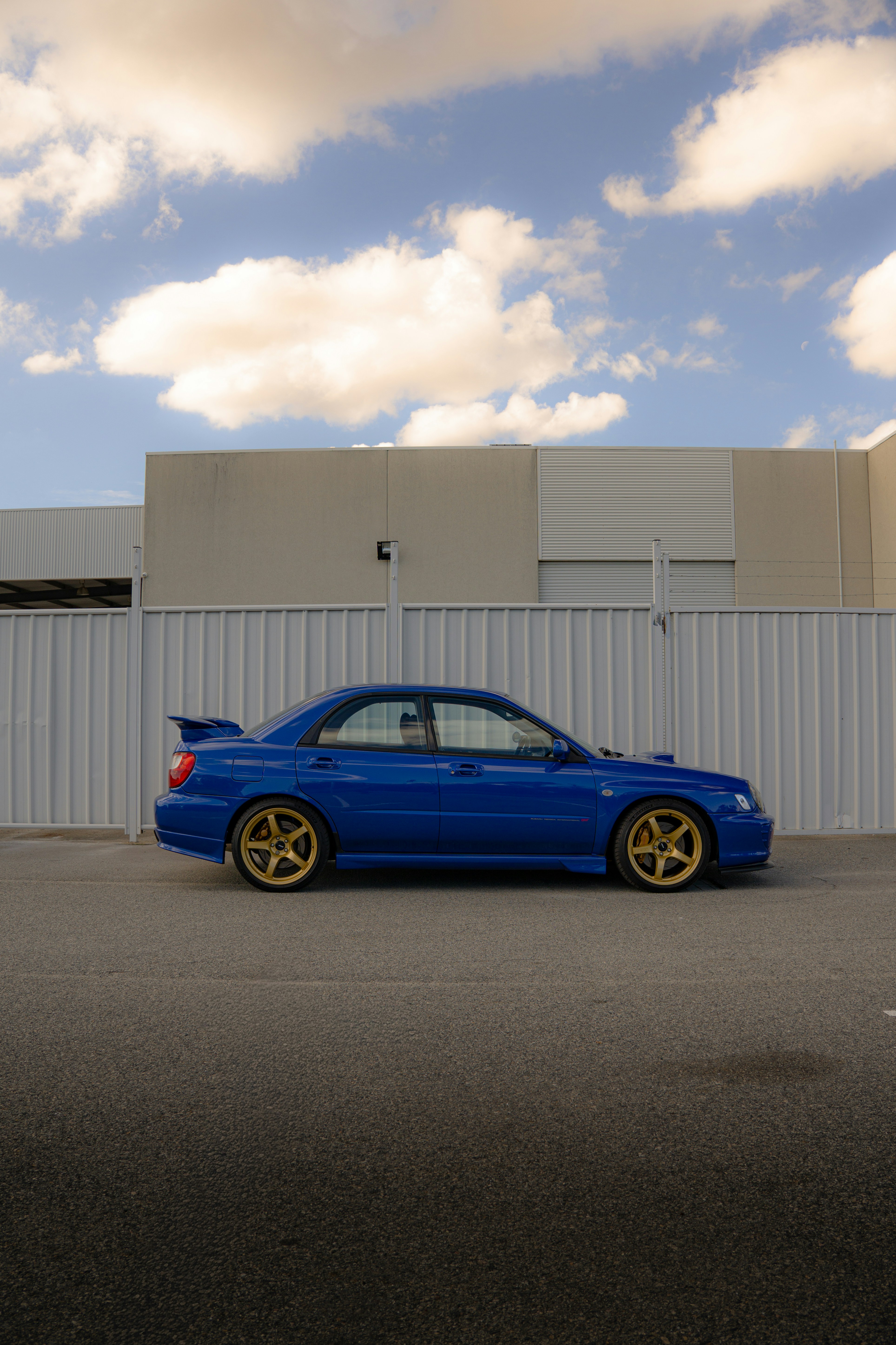 Blue Skyline: A Daring Stance of a Blue Coupe in an Industrial Oasis
