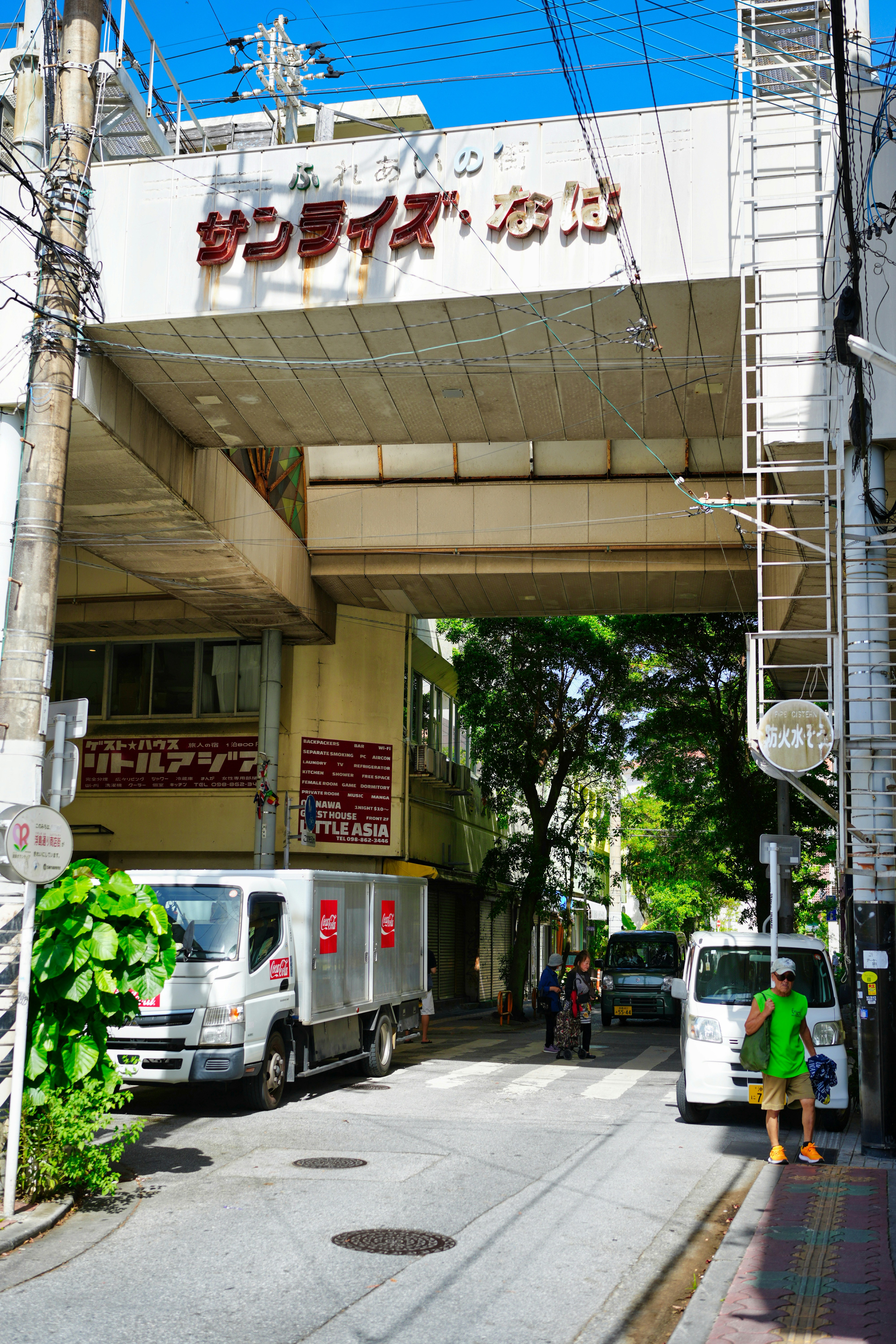 Urban Gateways: A Sunny Street Under Neon Sign