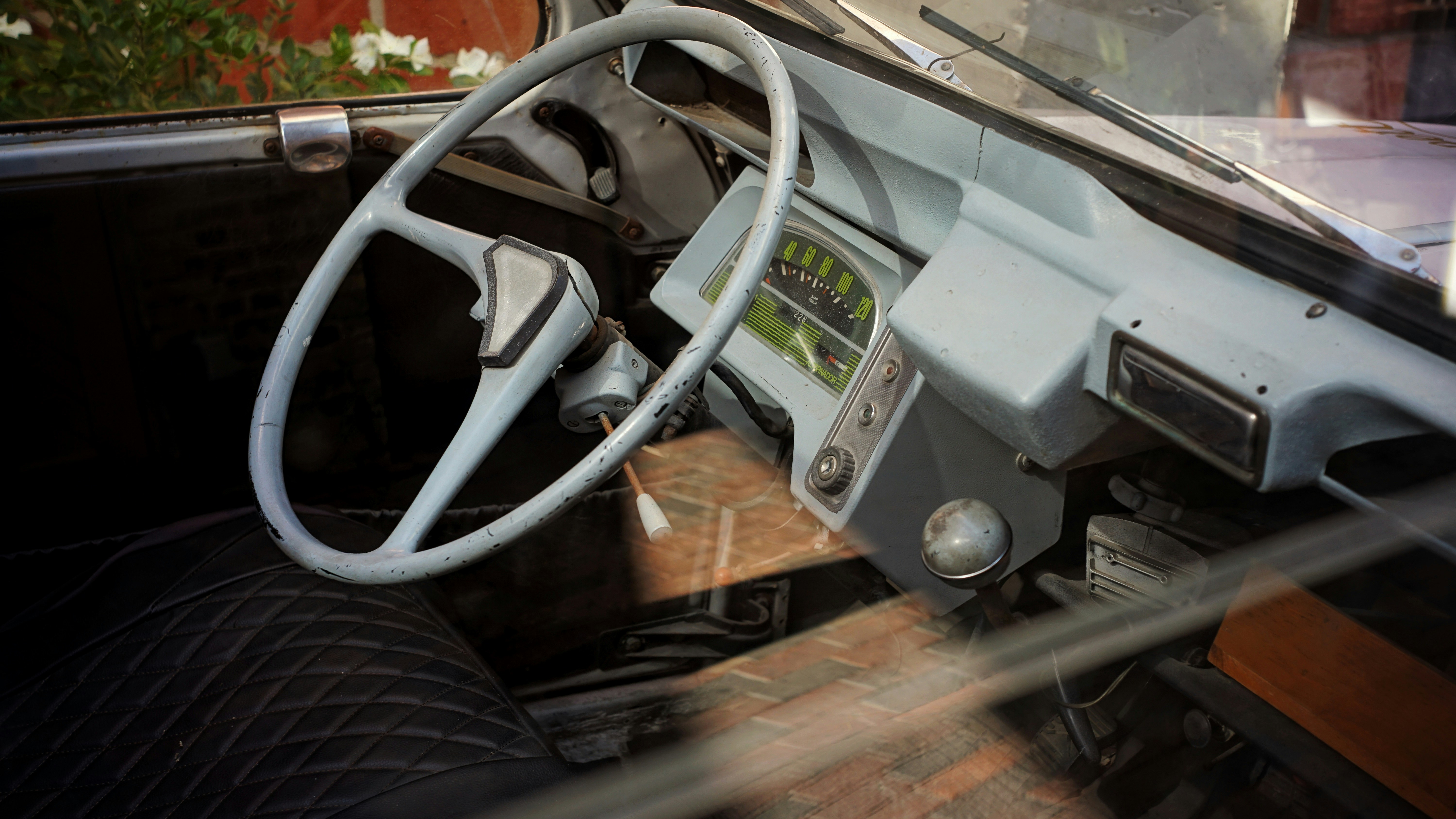 Dusty Dashboard Echo: A Vintage Steering Wheel Under Glassy Light
